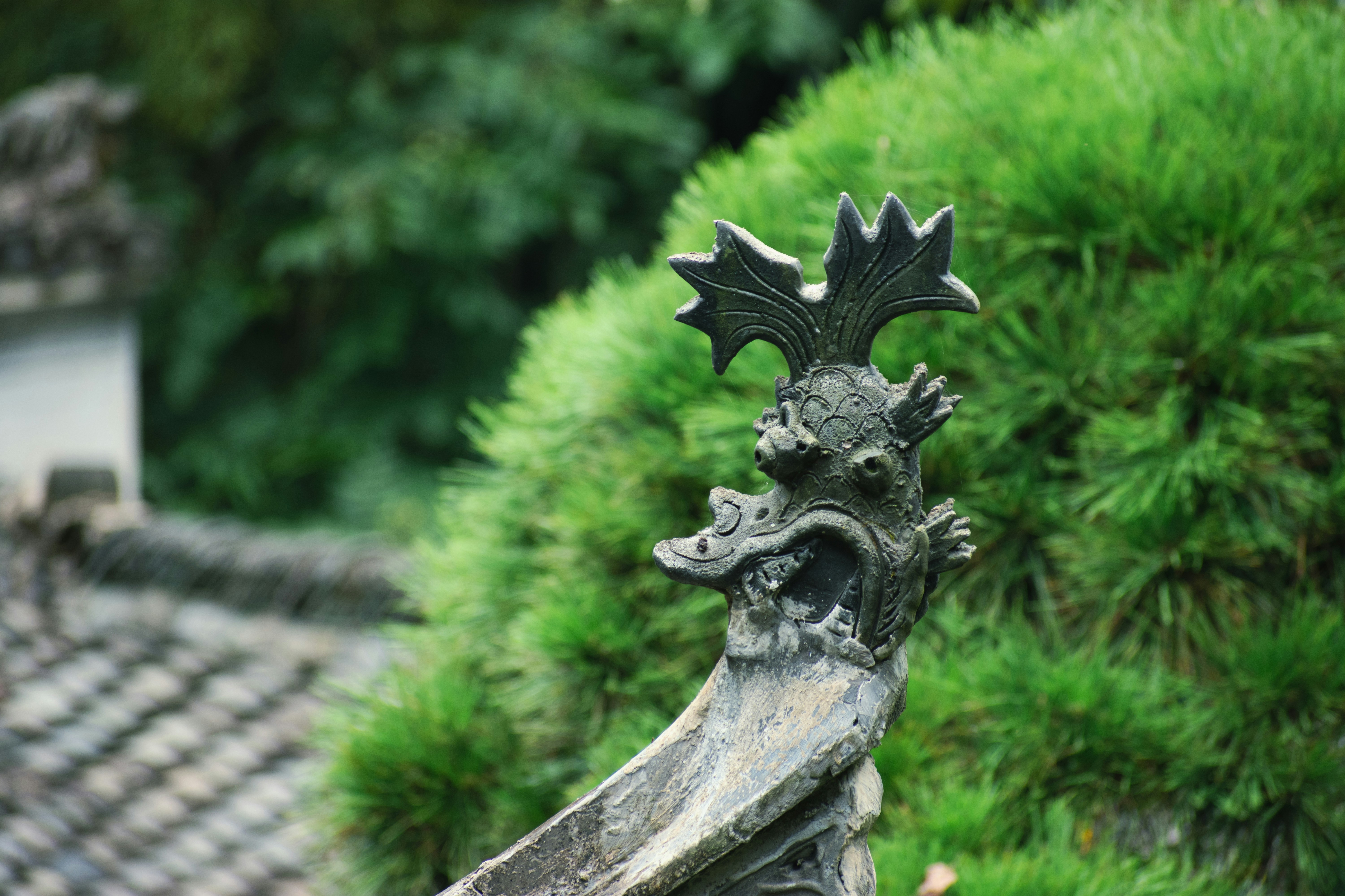 Dragon on the Ridge: A Weathered Roof Ornament Amid Japanese Garden Greenery