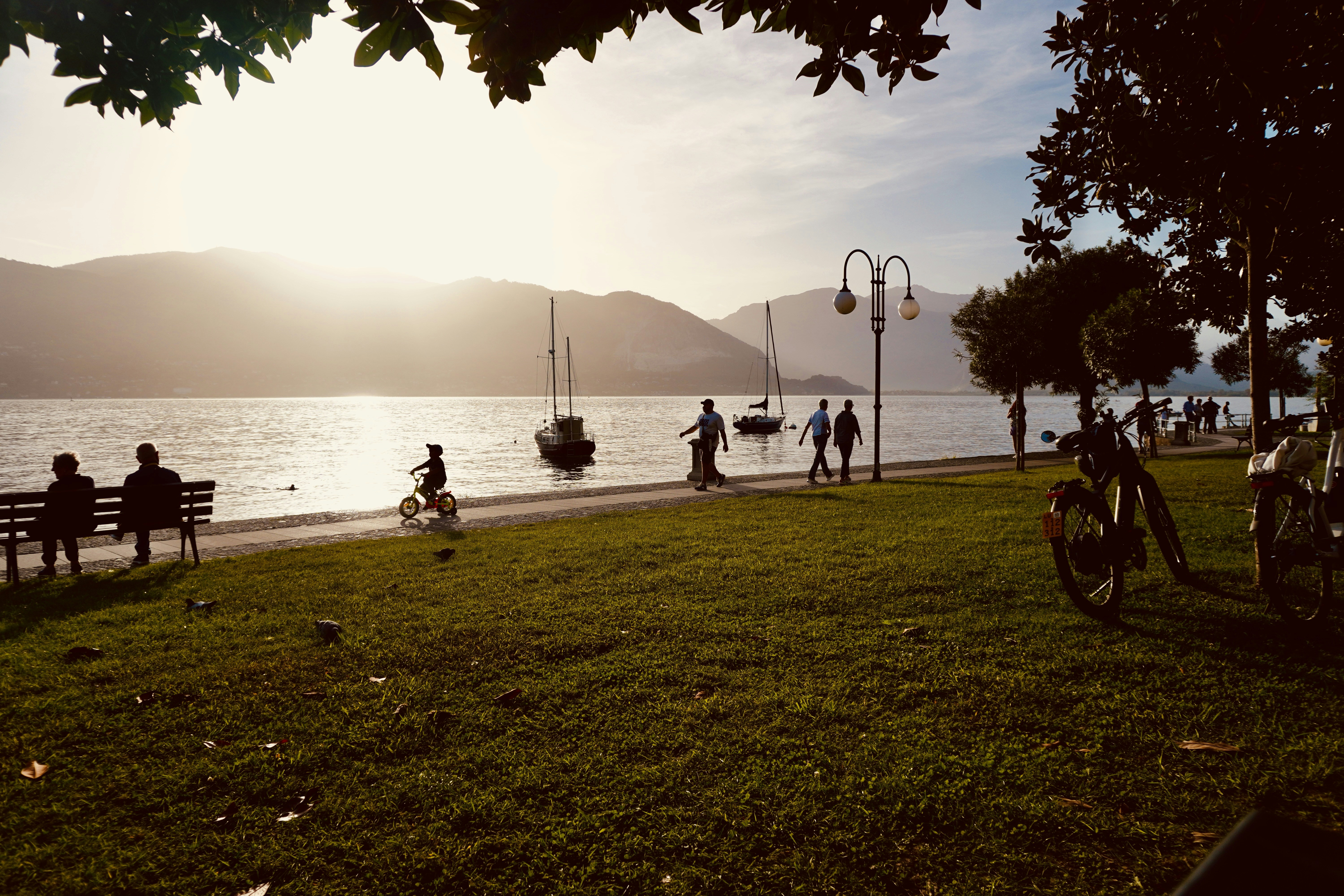 Sunset Promenade: Silhouettes, Boats, and Quiet Activity by the Lake