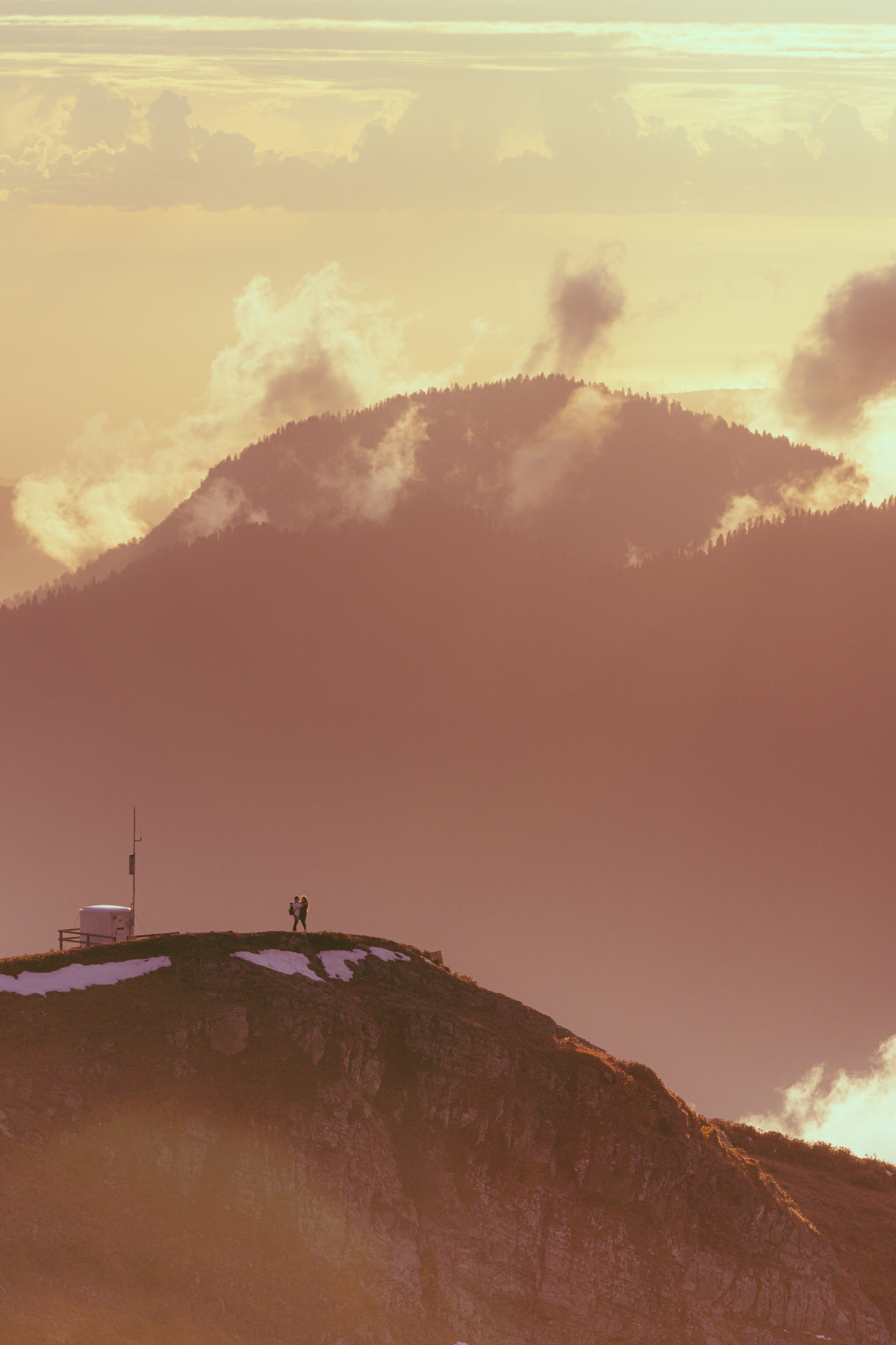 A couple in love at the top of a mountain during sunset.