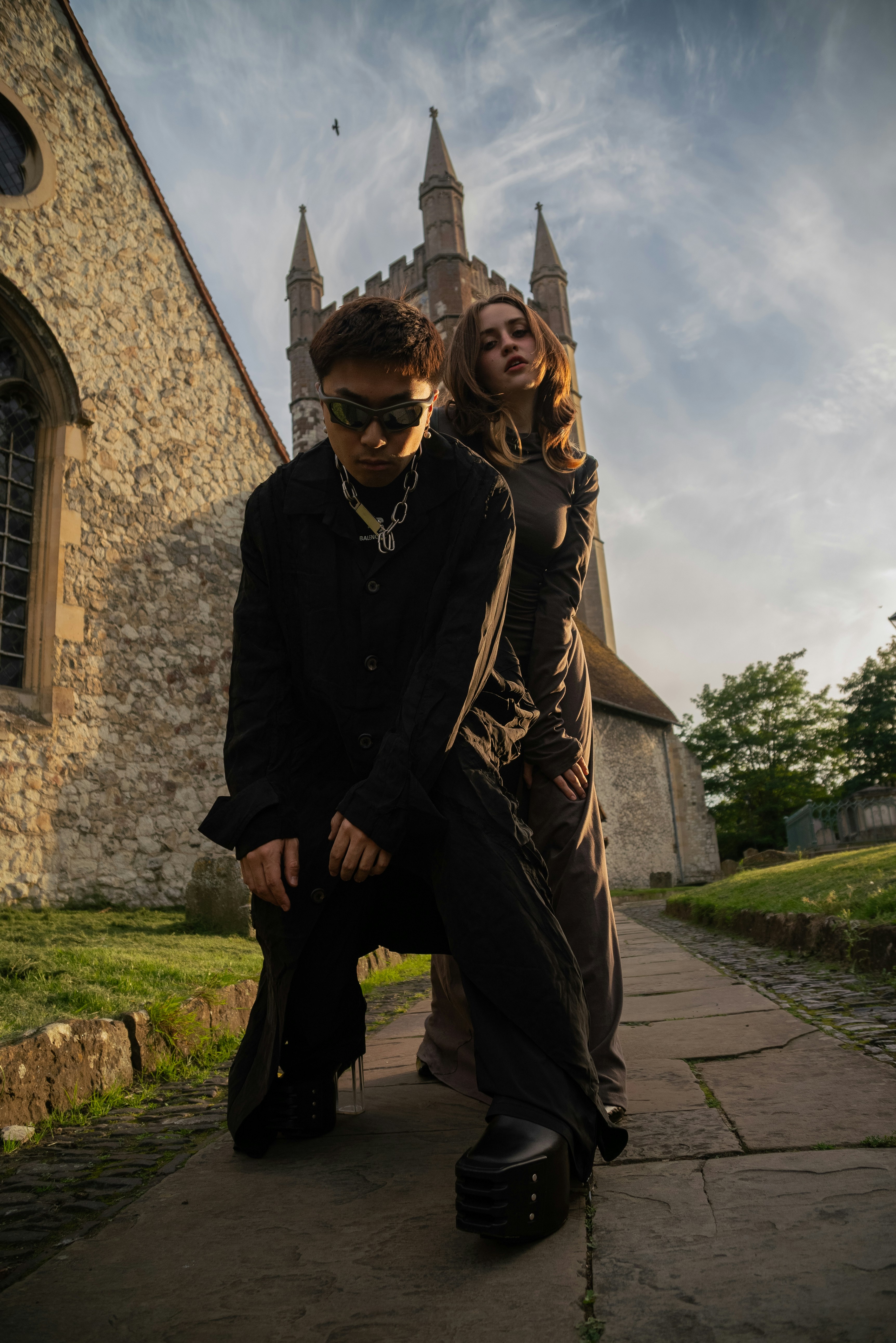  gothic duo stride toward the camera under a medieval church spire