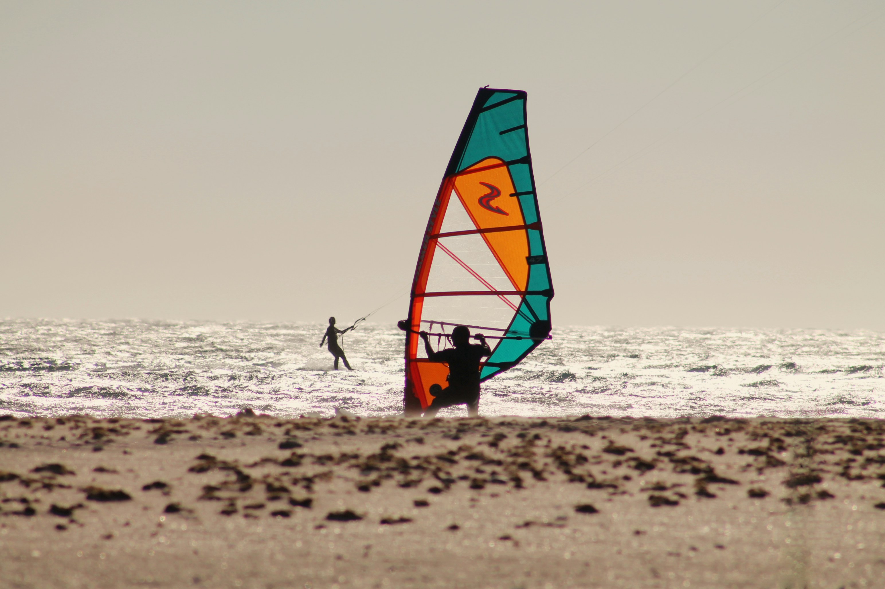 A man riding a wind sail on top of a sandy beach photo – Free ...