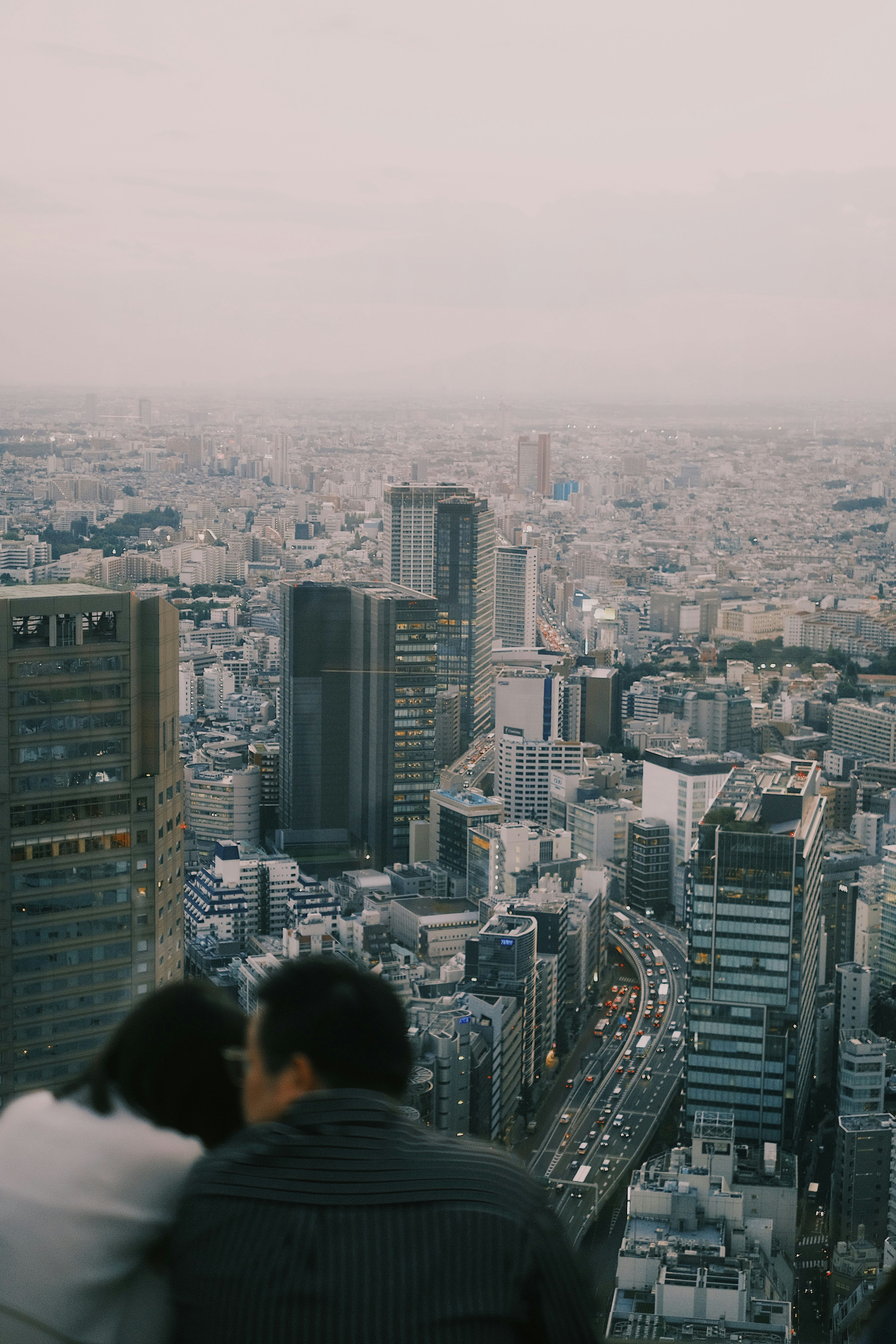 Two people sitting on a ledge overlooking a city photo – Free Woman ...
