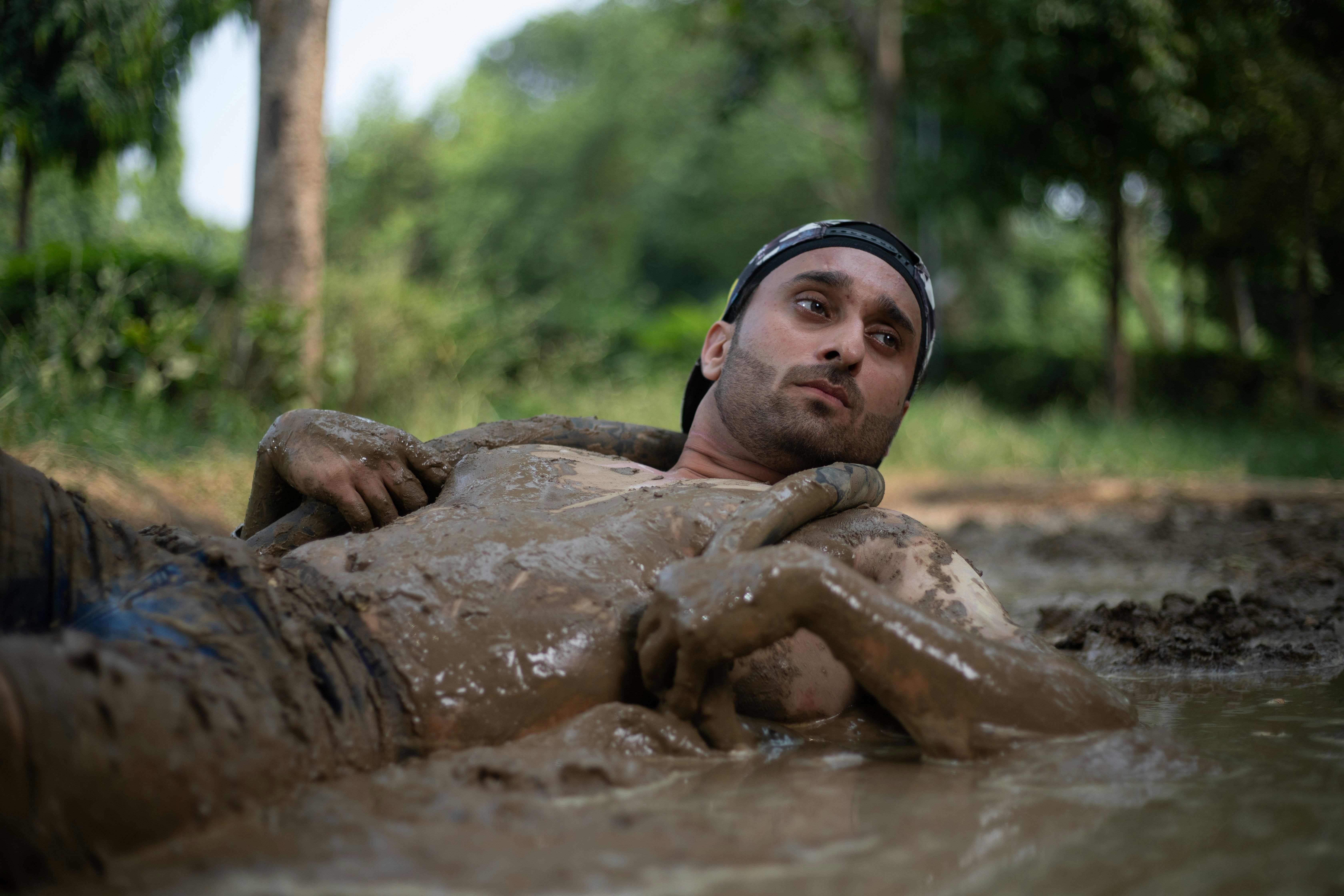 A man laying in the mud in a river photo – Free Mud Image on Unsplash
