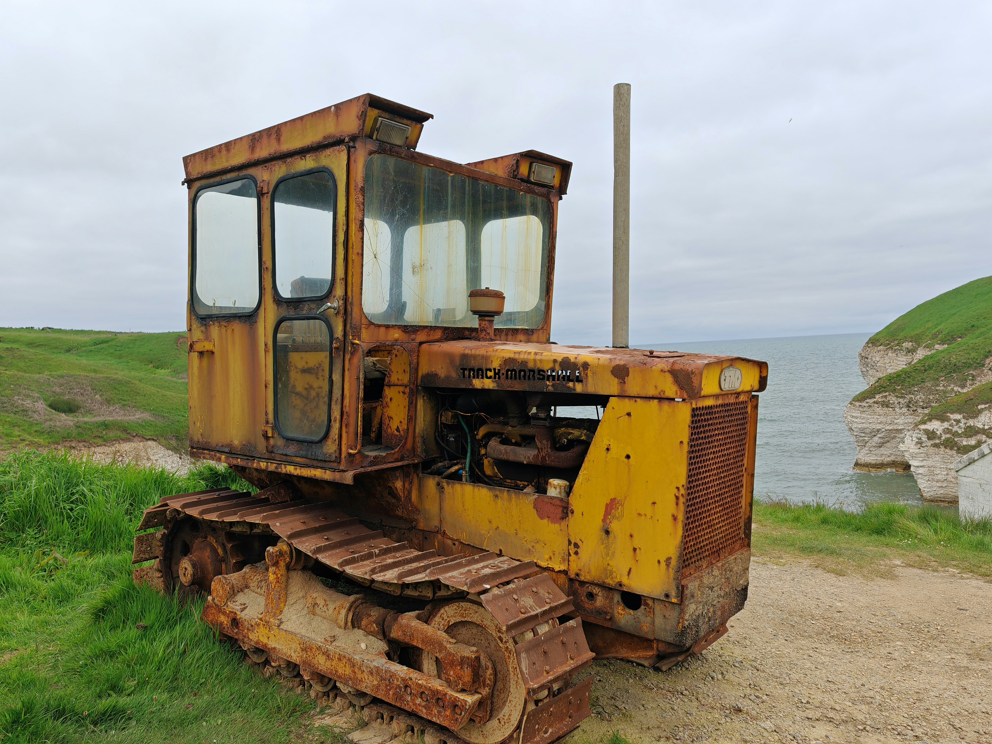Rusting Sentinel: An Antique Tracked Machine by the Cliffside