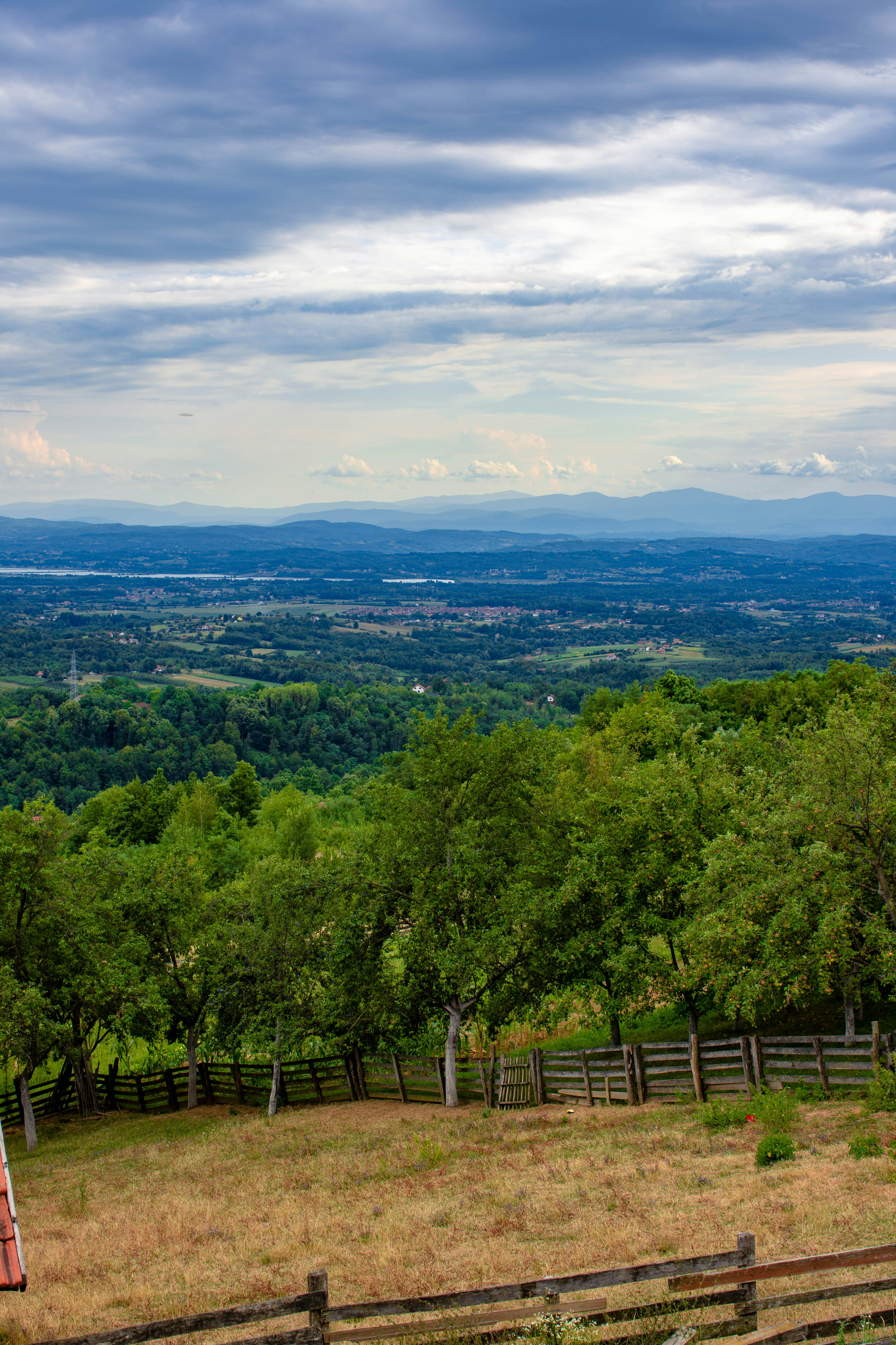 Fence-Lined Panorama: Layered Valleys Under a Cloud-Scattered Sky