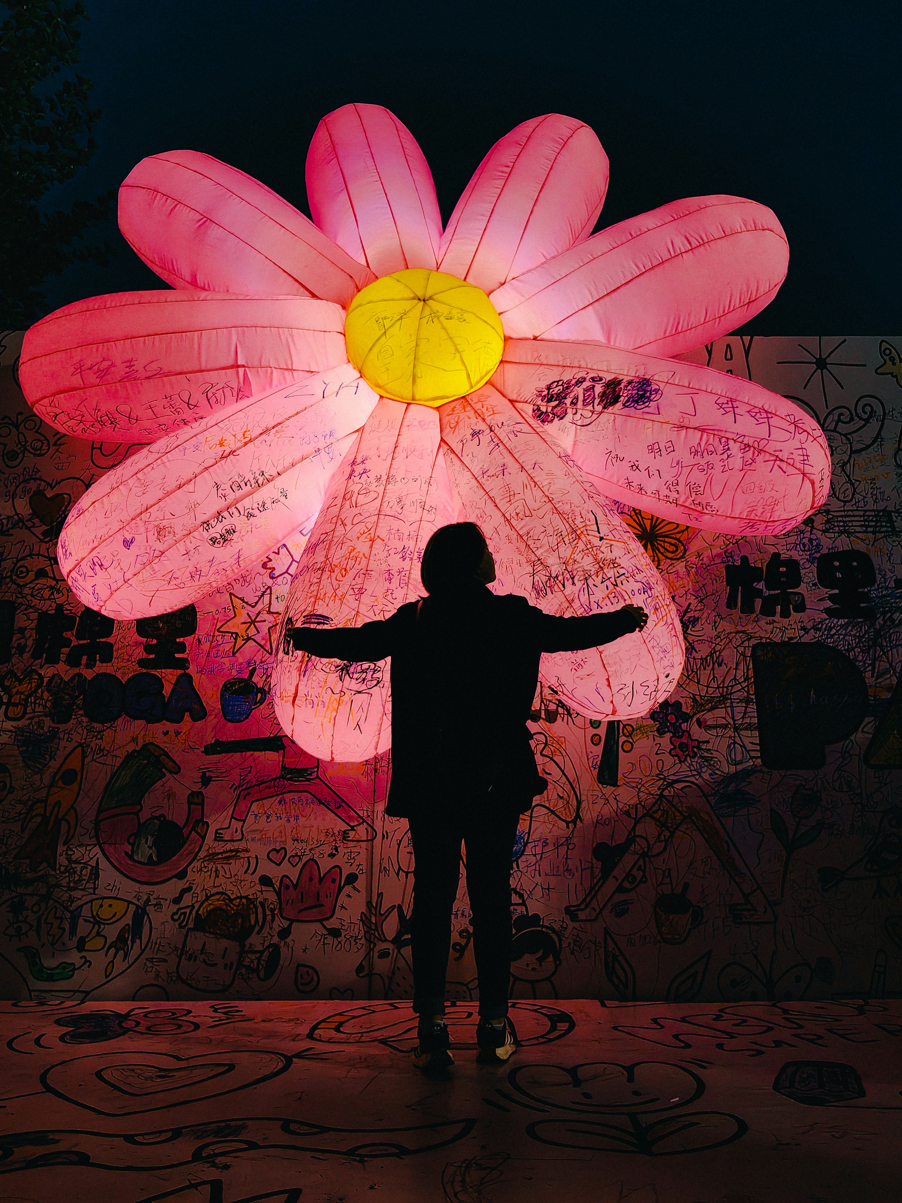 Luminescent Bloom: Night Portrait Beneath a Giant Pink Flower