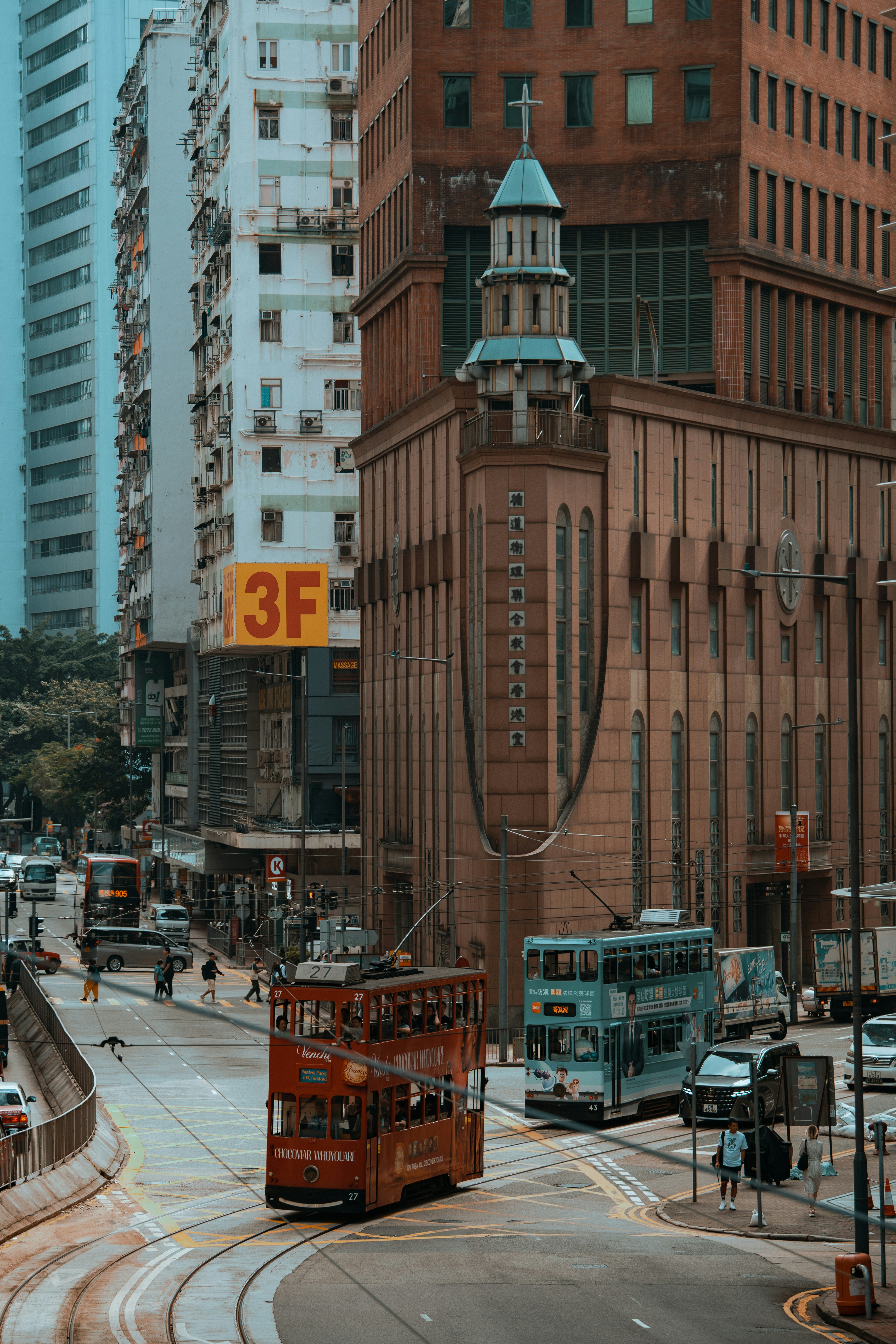 Red tram weaving through a canyon of brick and glass towers