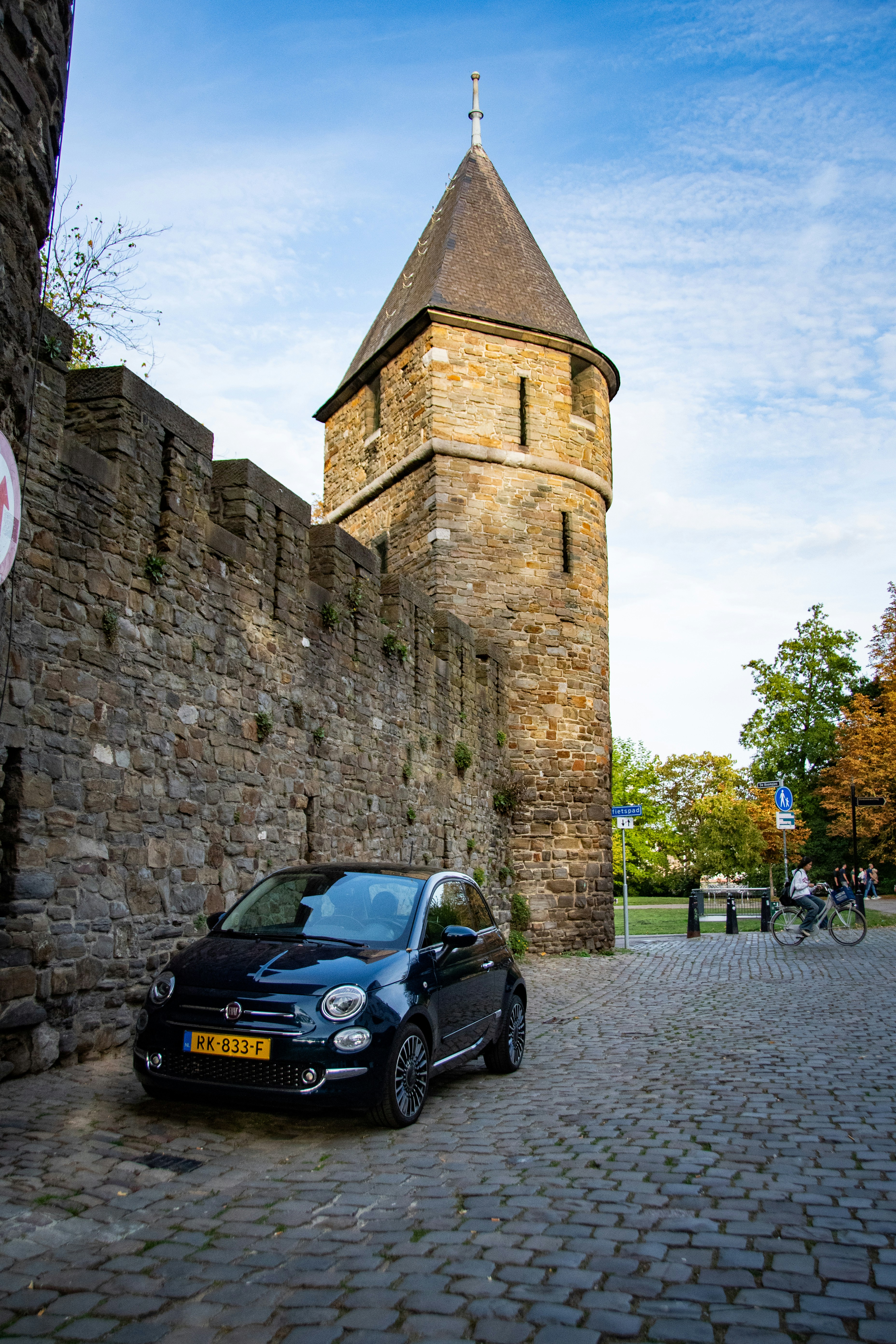 Turreted Gate Over a Quiet Cobblestone Street and a Black Fiat
