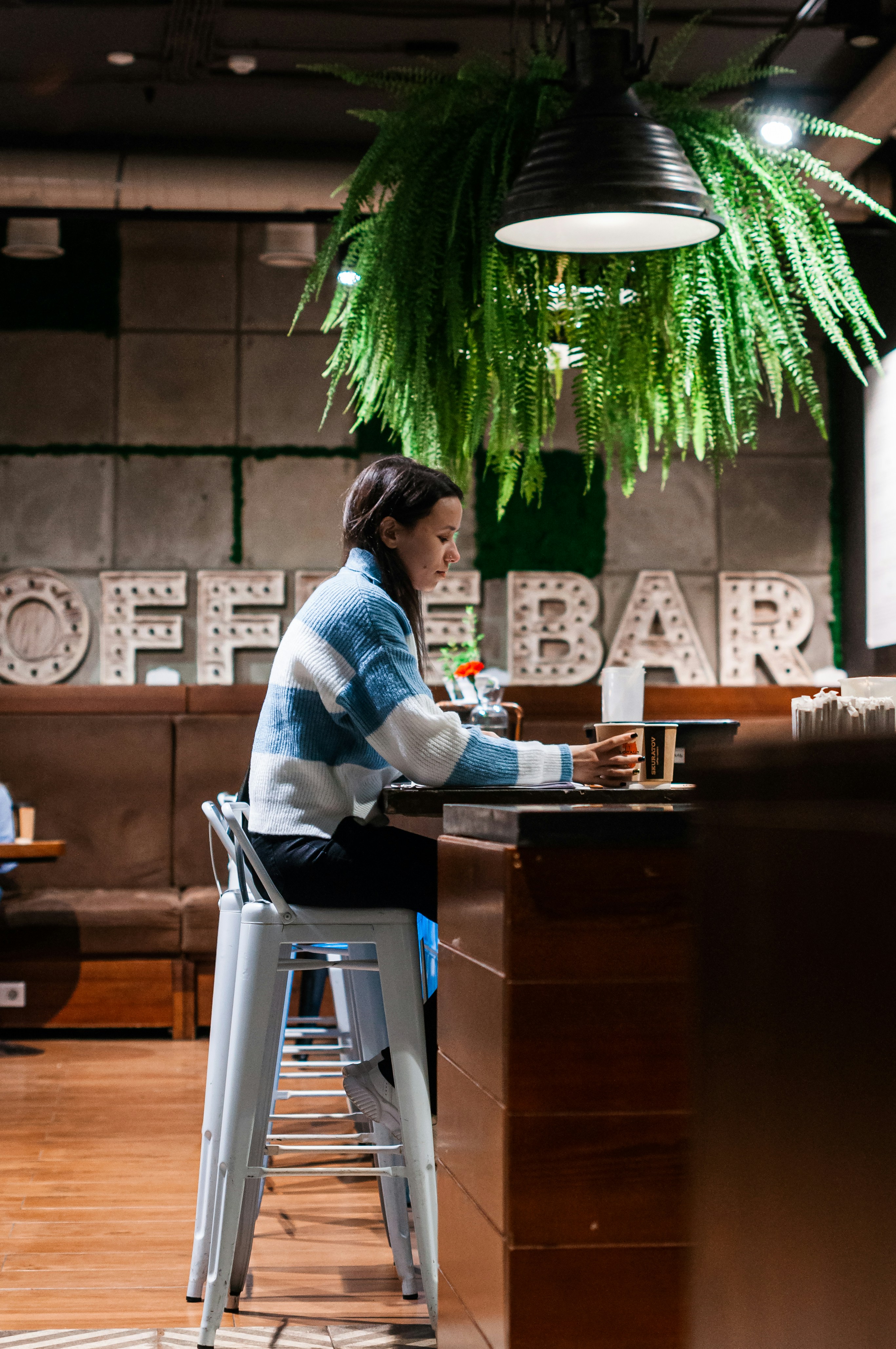 Quiet Moment at the Bar: A Woman in a Cozy Blue-Striped Sweater