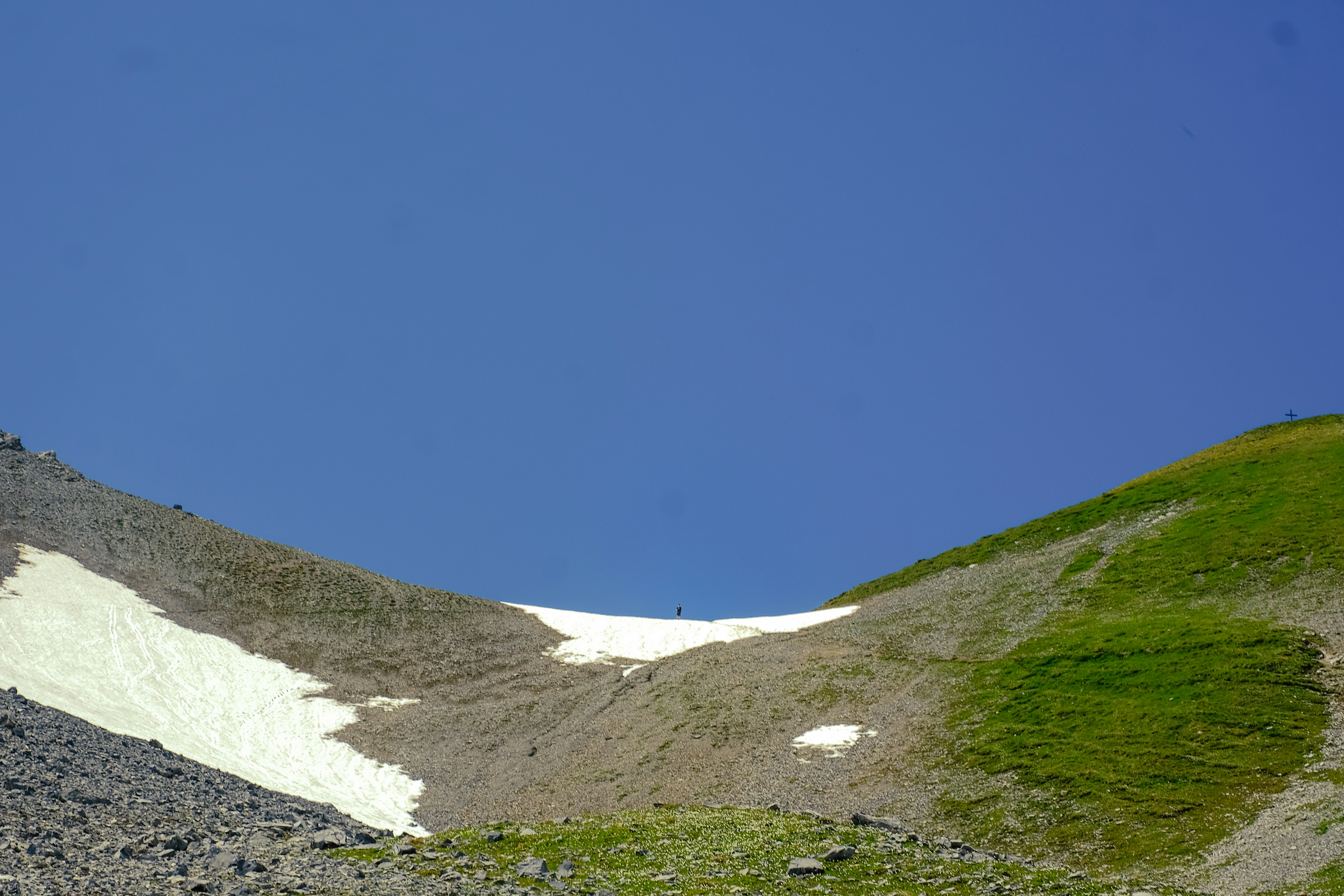Solitary Crest: A lone hiker stands on a wind-sculpted alpine ridge beneath a cobalt sky
