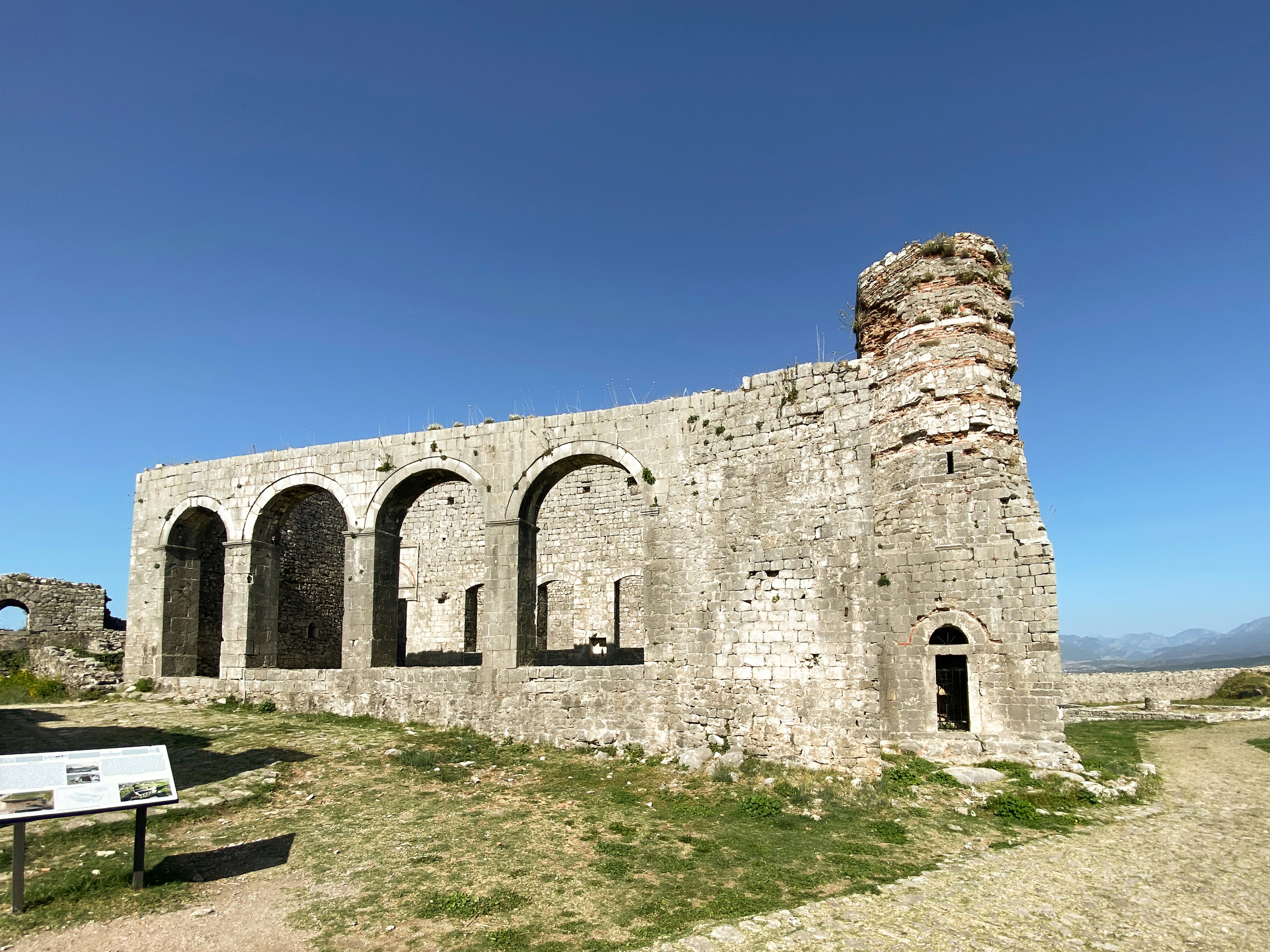 Sunlit Arcades: Weathered Ruins with Archways Against a Clear Blue Sky
