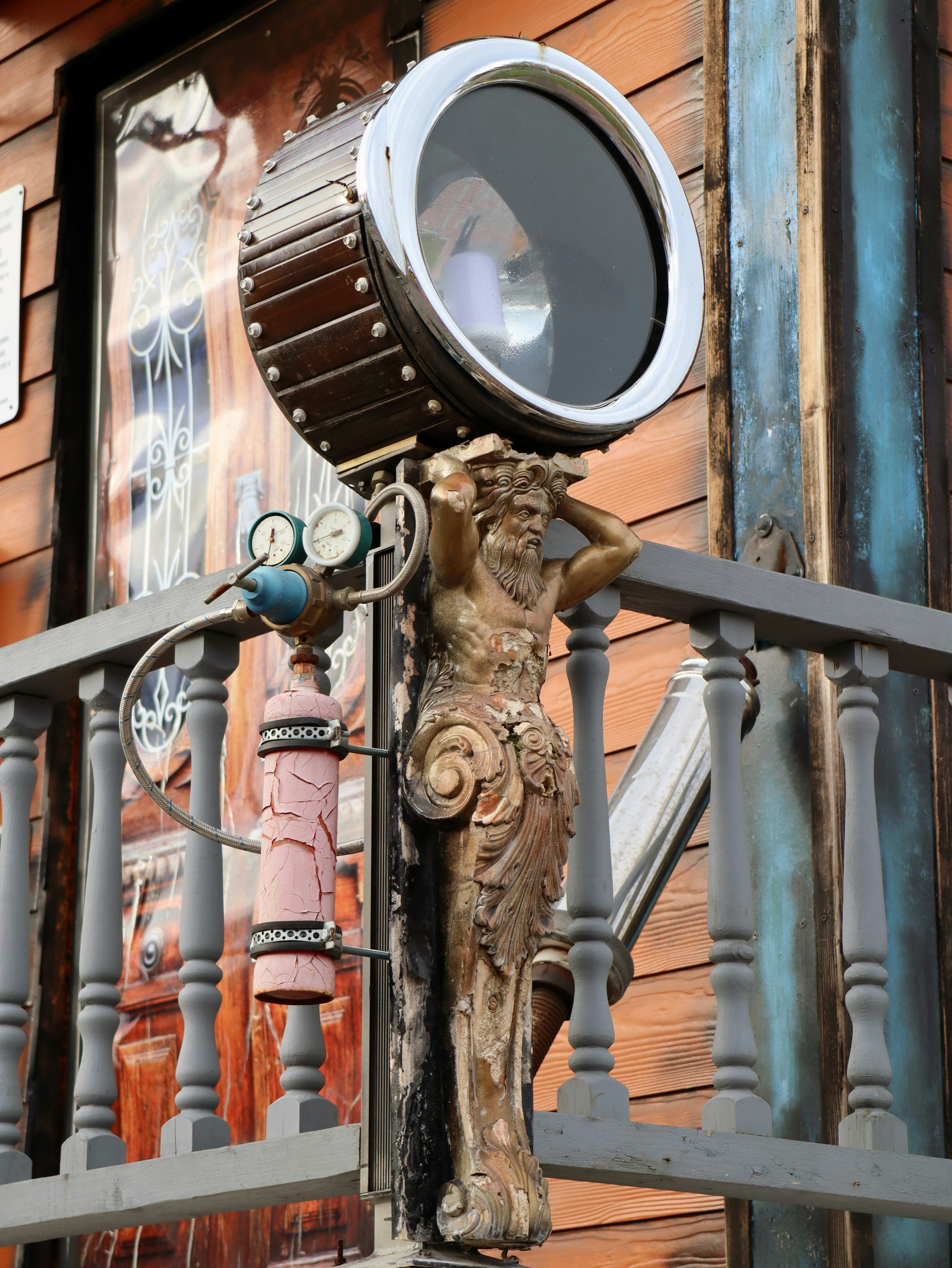 Giant Spotlight Crowned by a Carved Titan on a Weathered Balcony