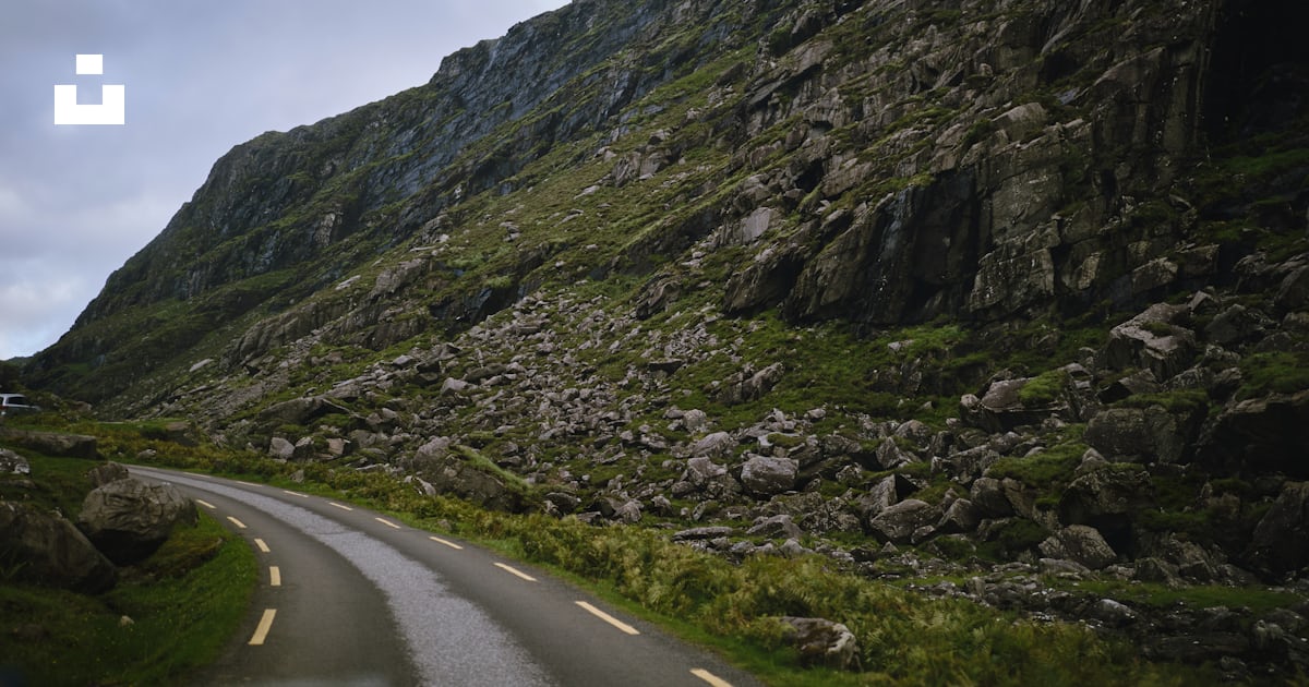 Foto Un coche que circula por una carretera junto a una montaña ... Foto Un coche que circula por una carretera junto a una montaña ...