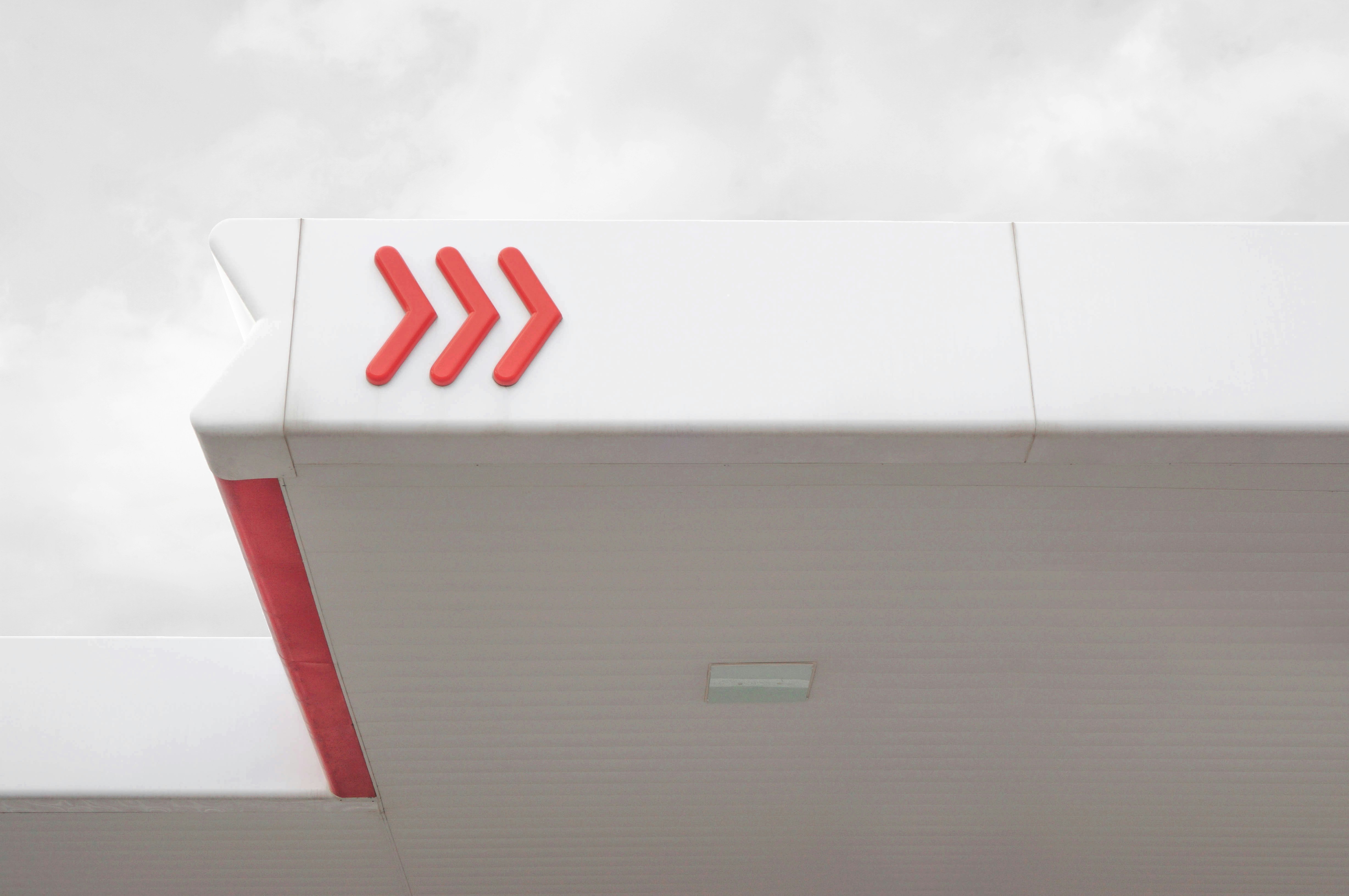 A red arrow sign on the side of a building photo – Free Red Image on ...