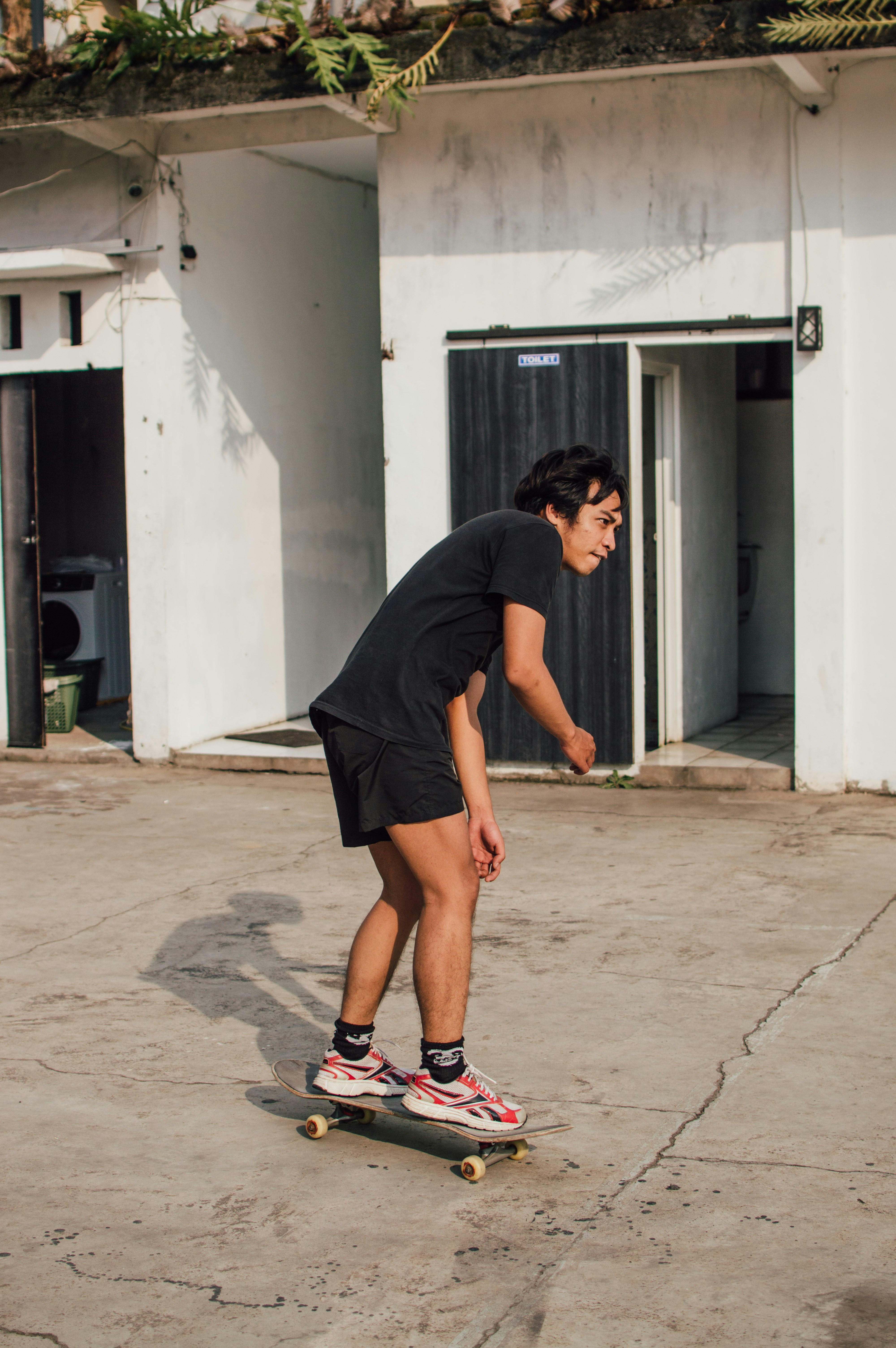 Lean and Glide: Skateboarder Cuts Through a Sunlit Courtyard