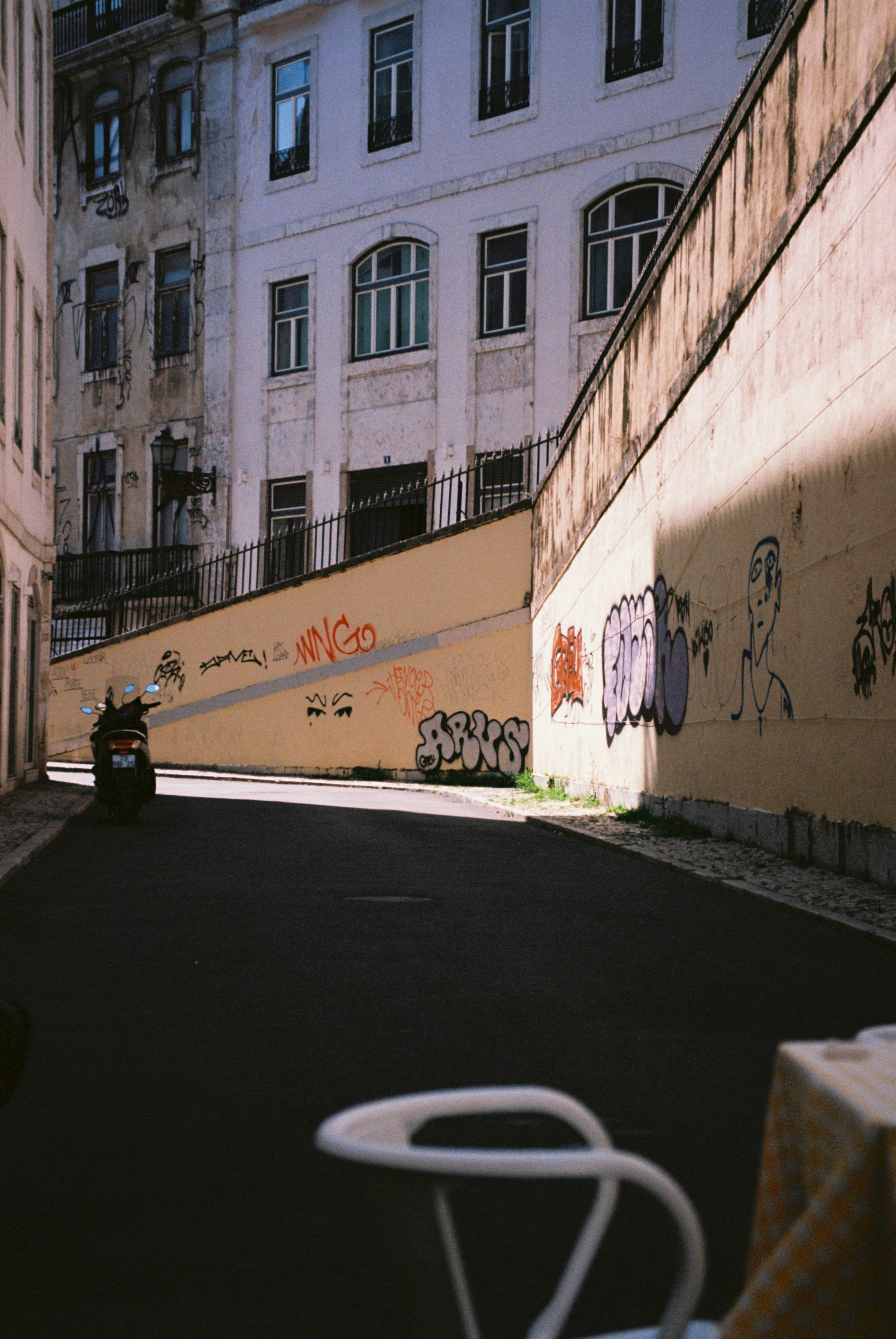 Shadowed Graffiti Alley: Scooter at the Edge of Sunlight