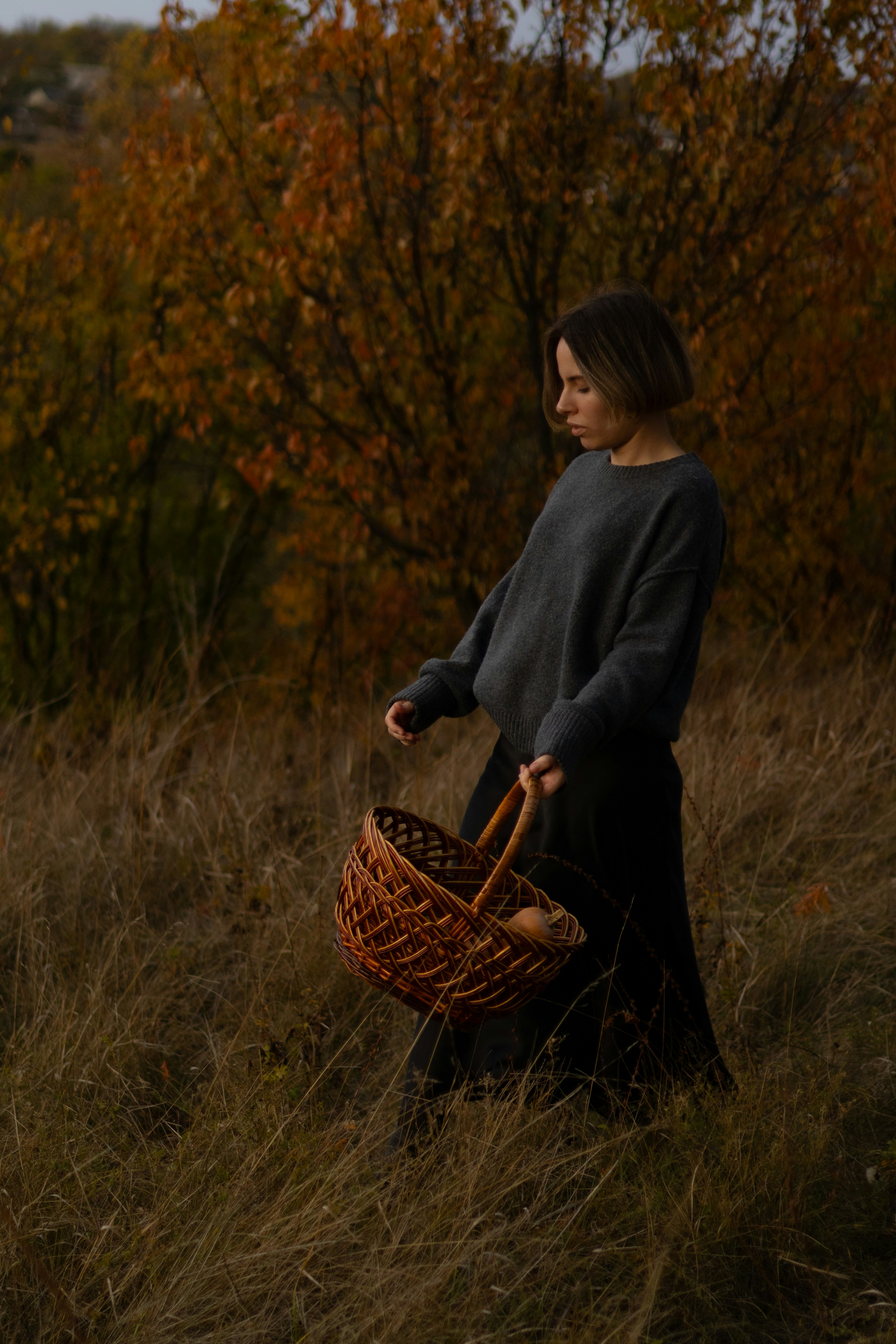 a woman standing in a field holding a basket