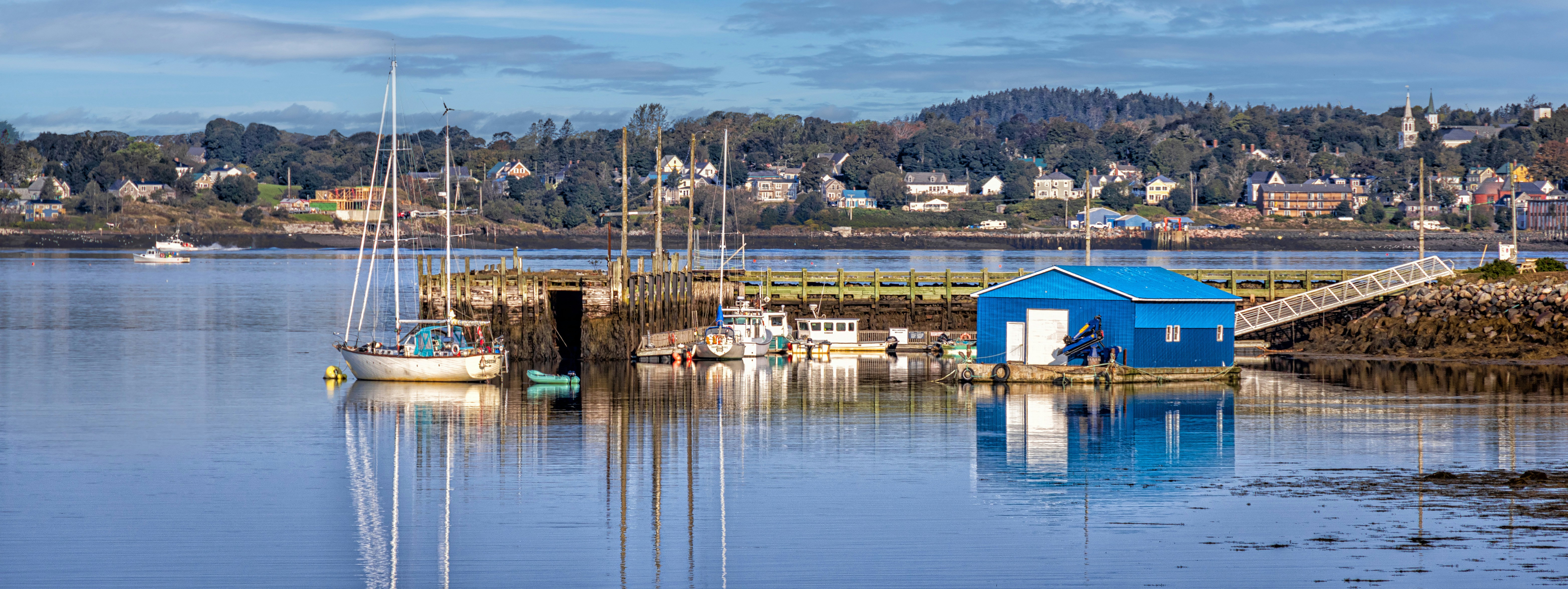 Azure Quay: Still Waters Reflect a Blue Boathouse and Sails