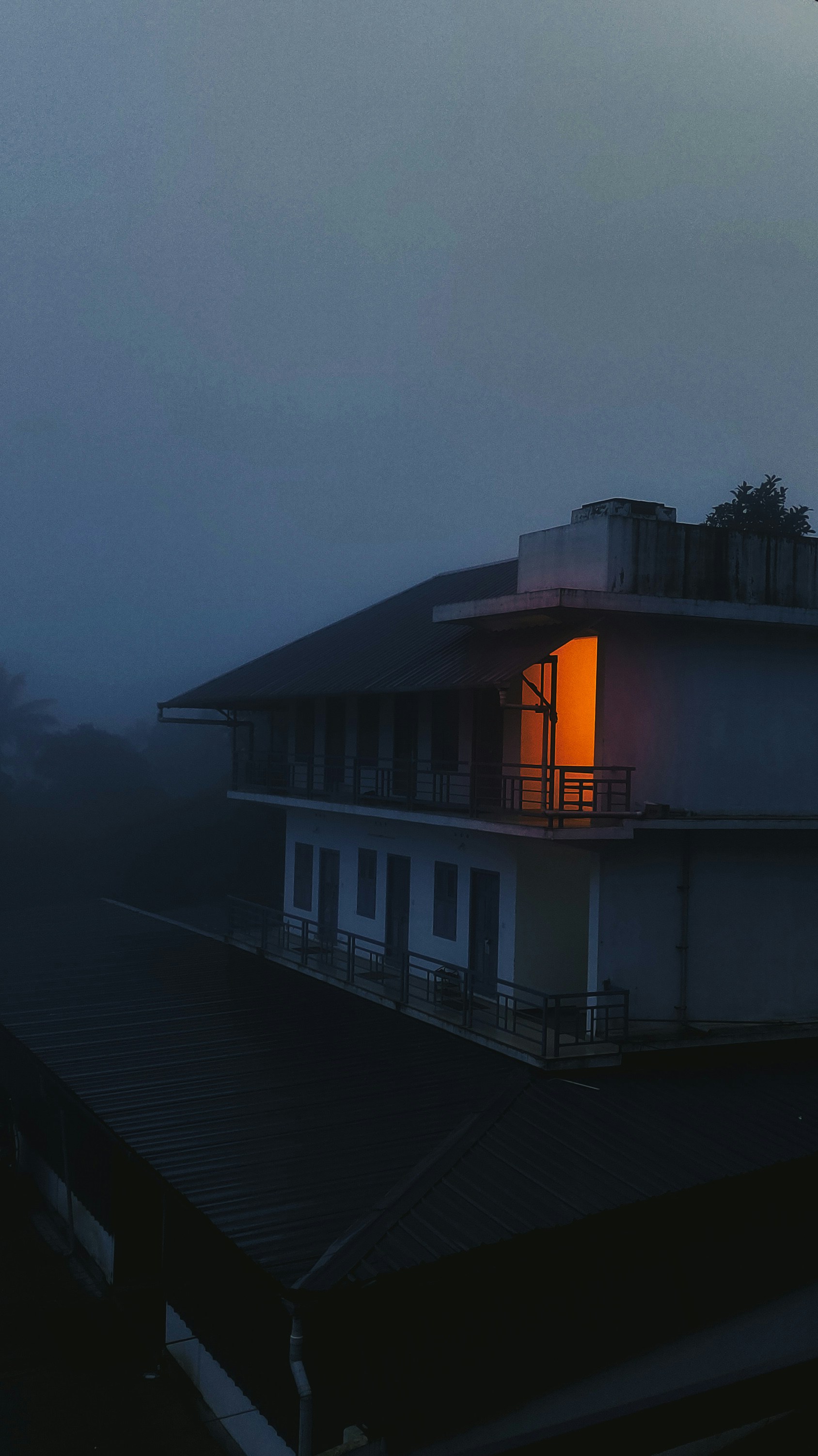 Orange Glow Behind a Balcony Door in Foggy Dusk