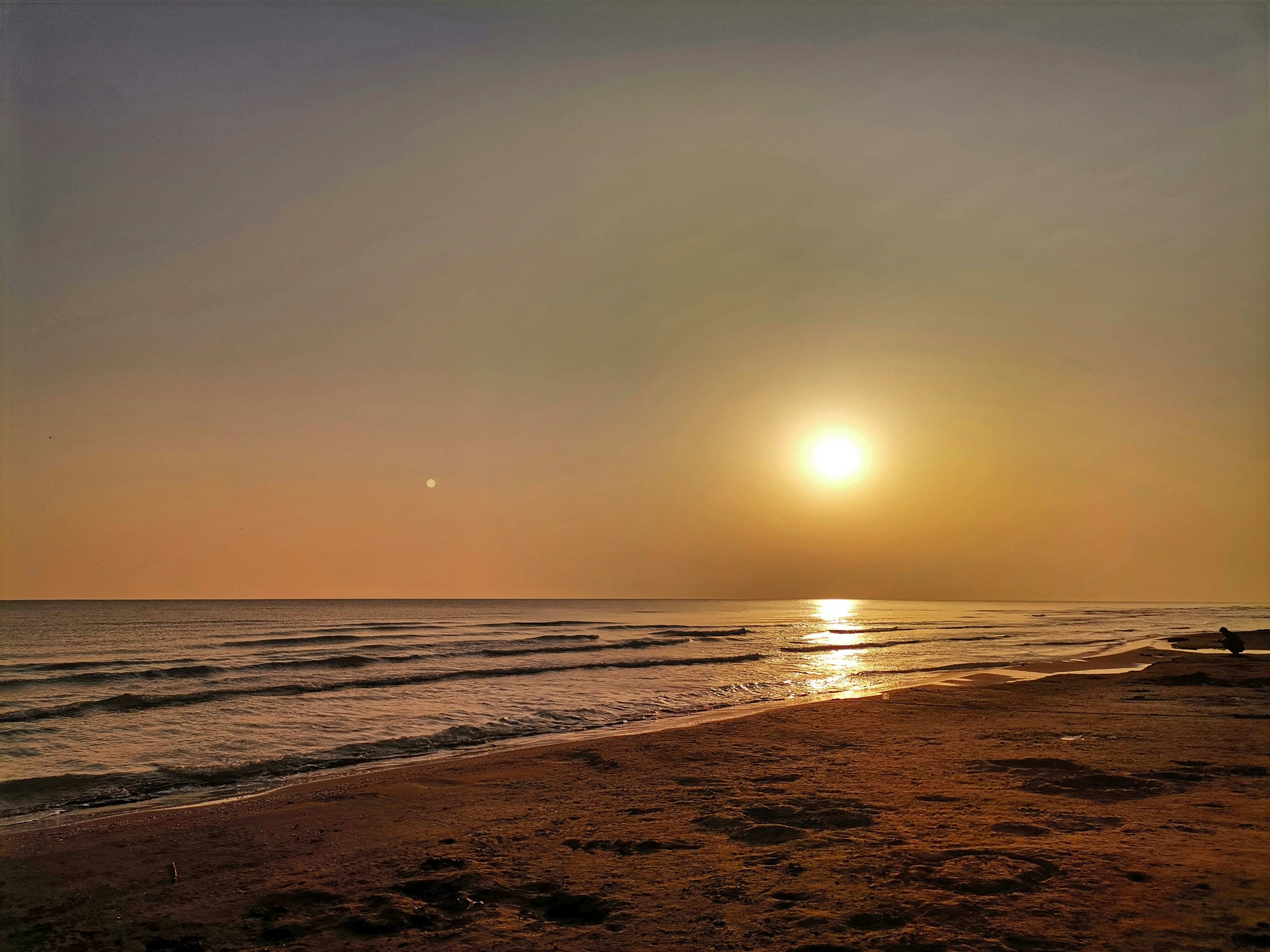 Foto El sol se está poniendo sobre el océano en la playa – Imagen ...