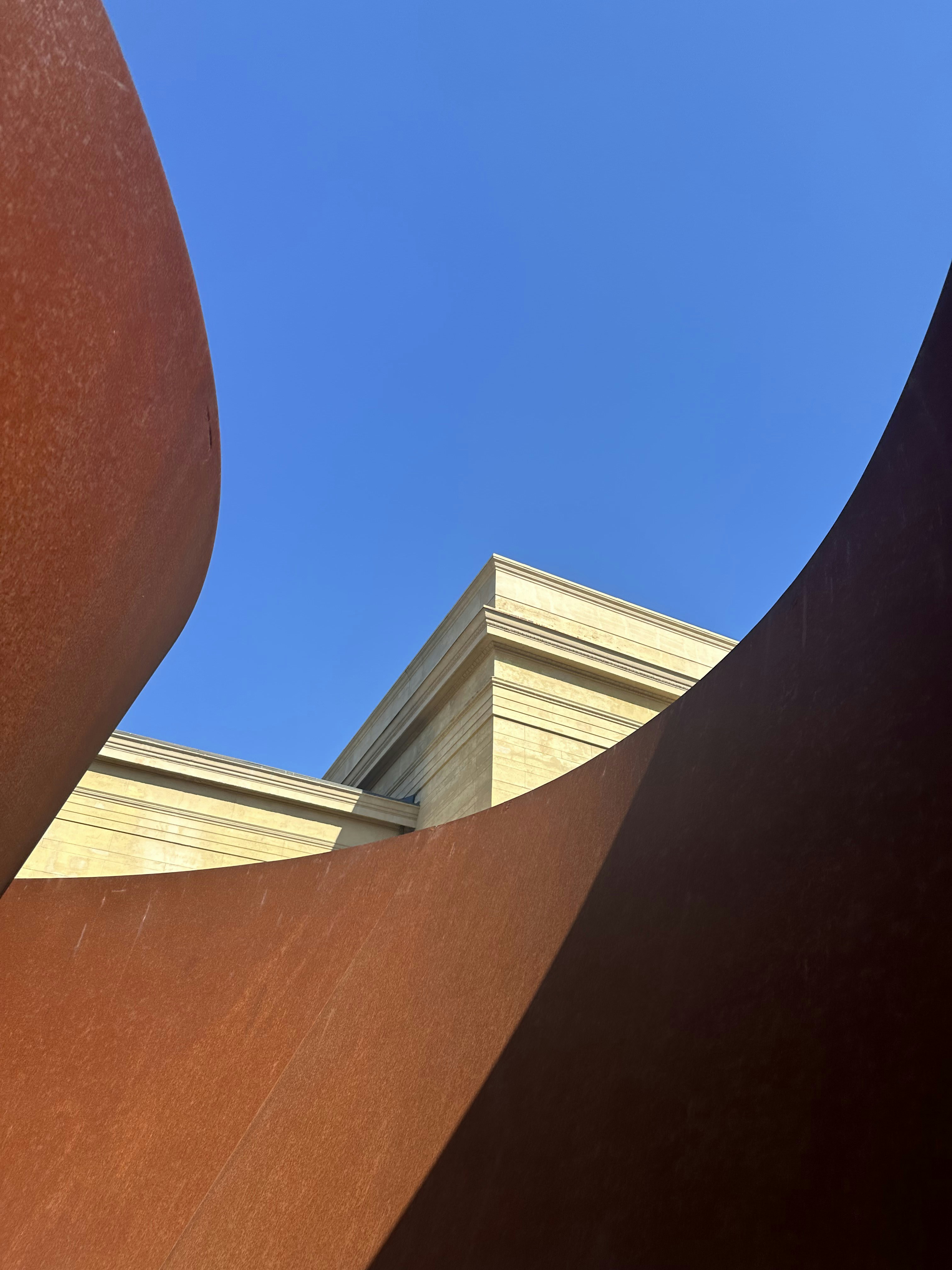 Rust-Colored Arcs Framing a Classical Facade Under a Cerulean Sky