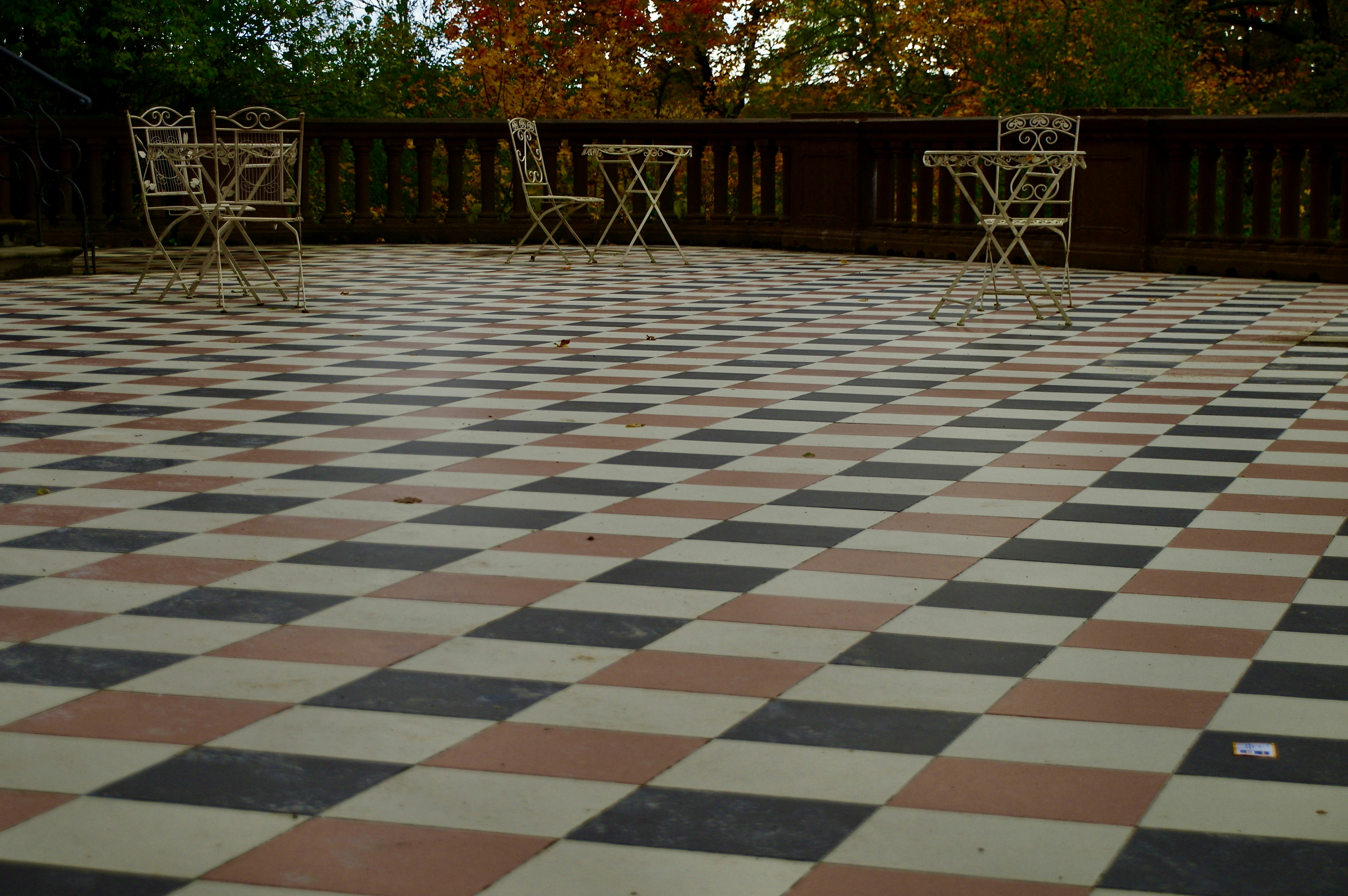 Autumn Checkered Terrace: Quiet Bistro Tables Beneath a Wooden Railing