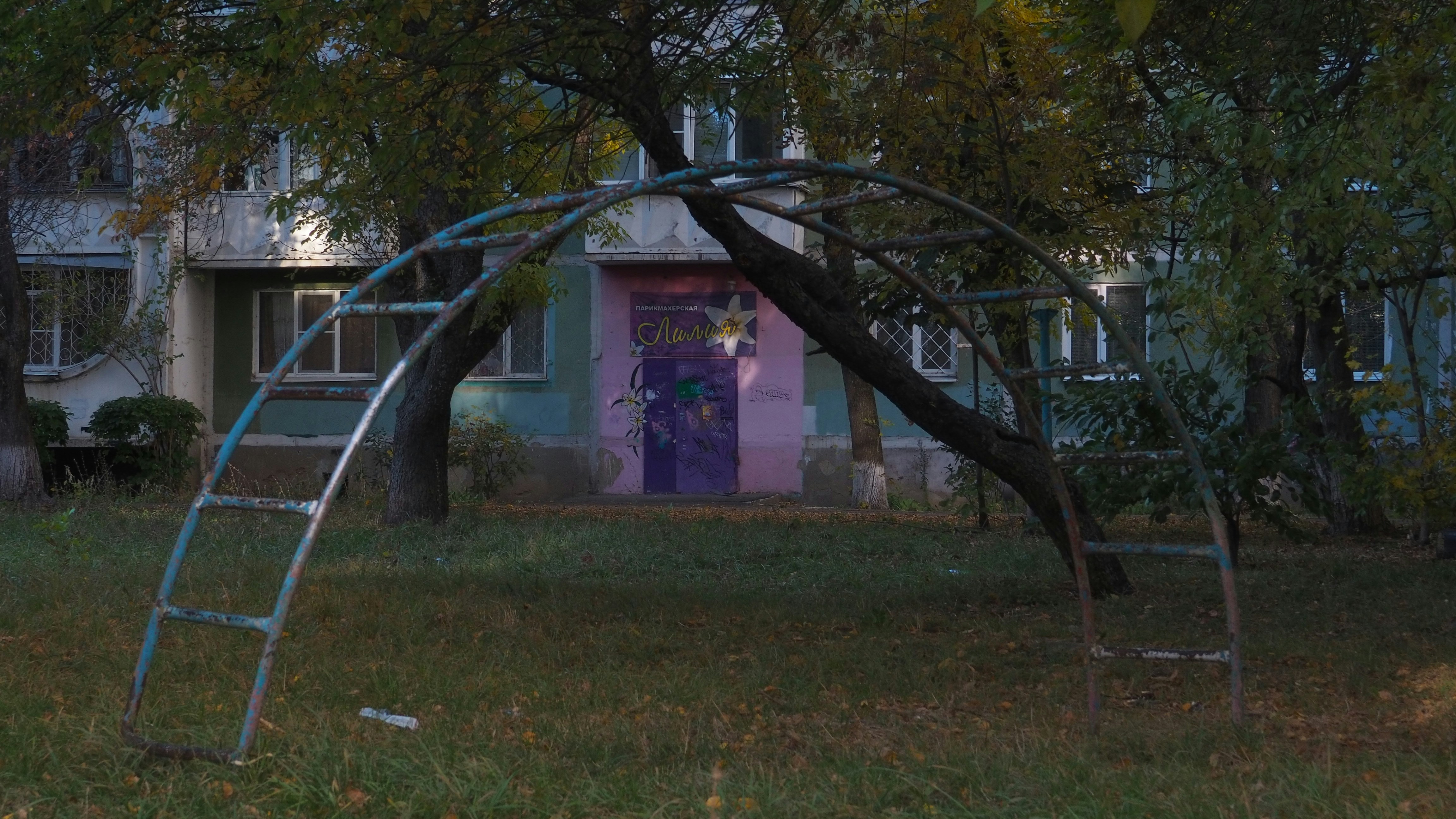 Purple Doorway Beneath a Weathered Metal Arch in a Quiet Courtyard