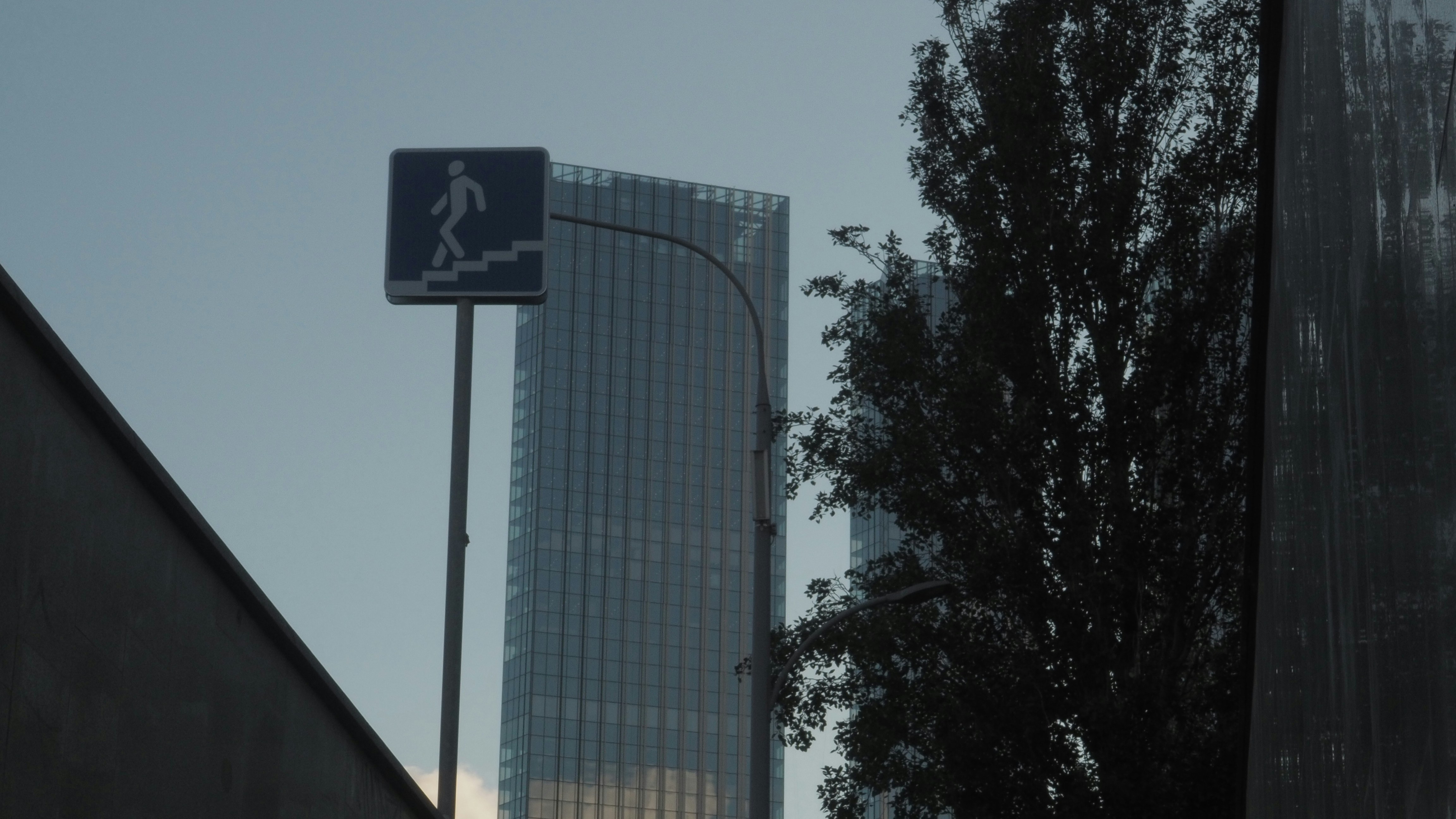Azure Glass Tower Framed by a Street Sign and Quiet Foliage