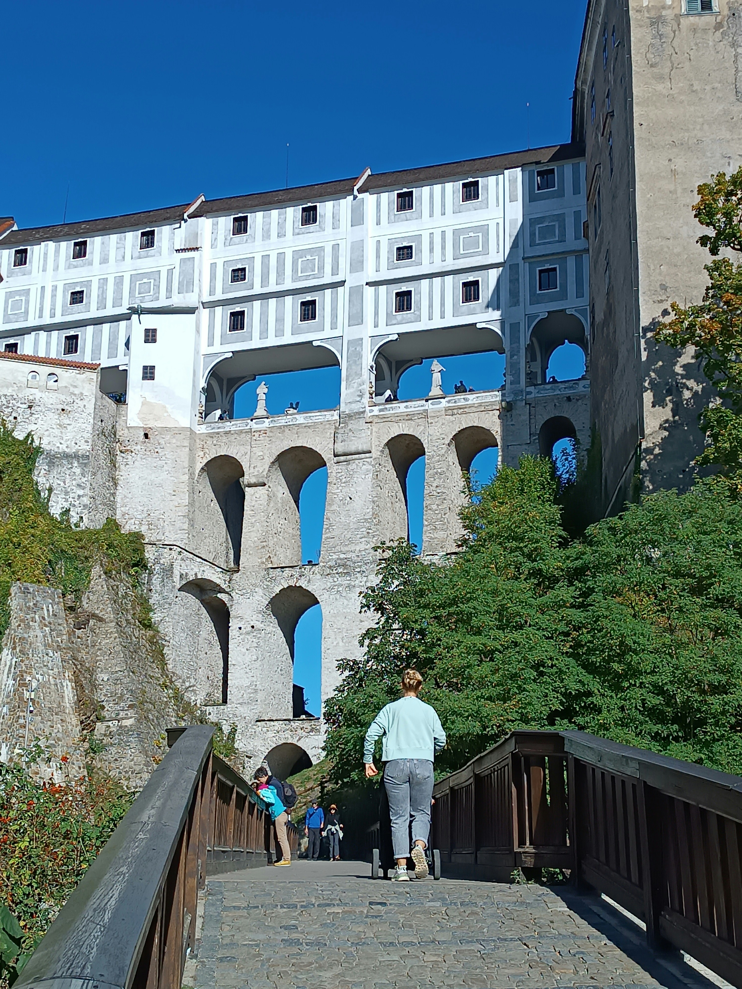 A man walking down a stone walkway next to a tall building photo – Free ...