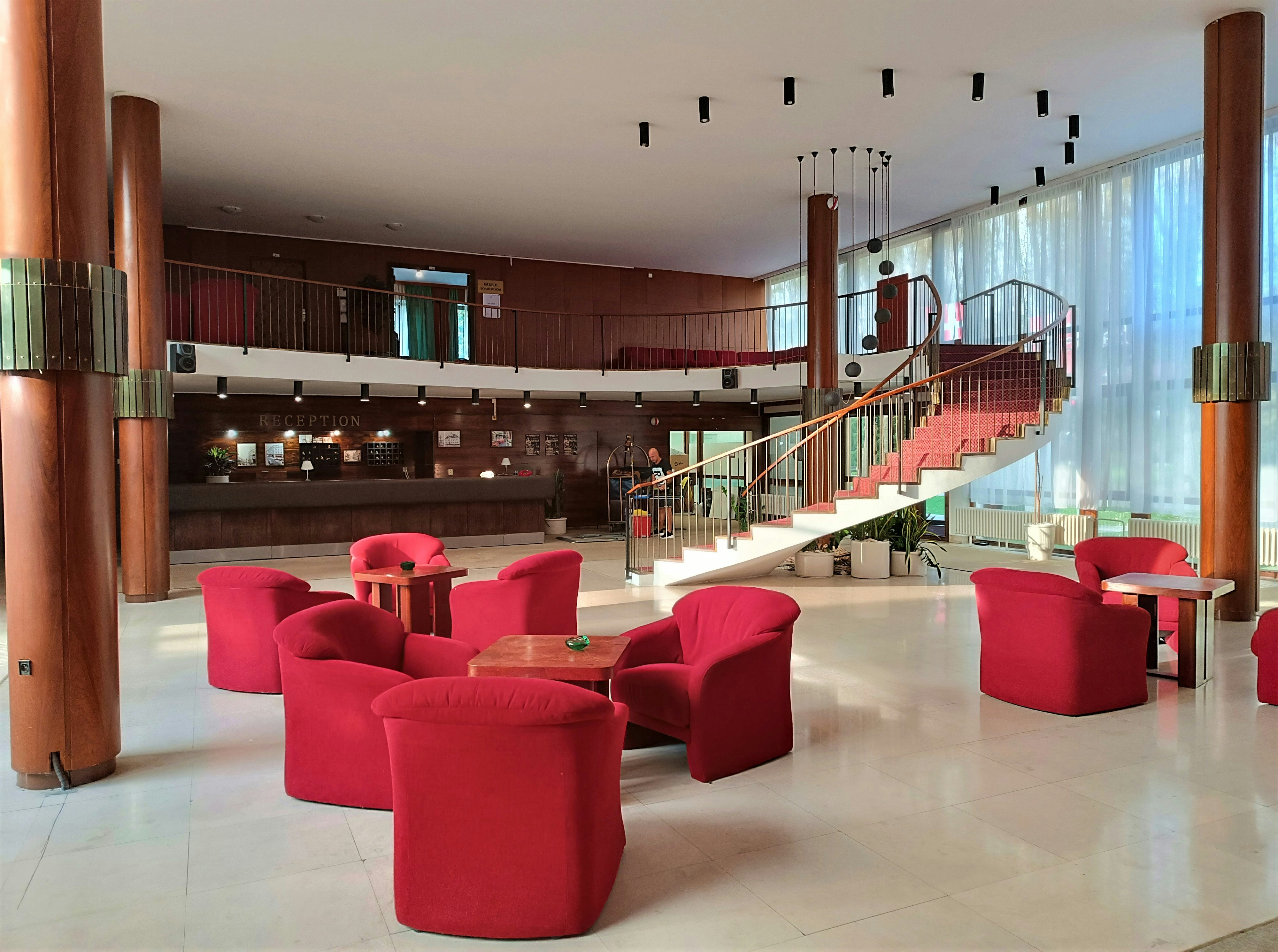 A lobby with red chairs and a spiral staircase photo – Free Piešťany ...