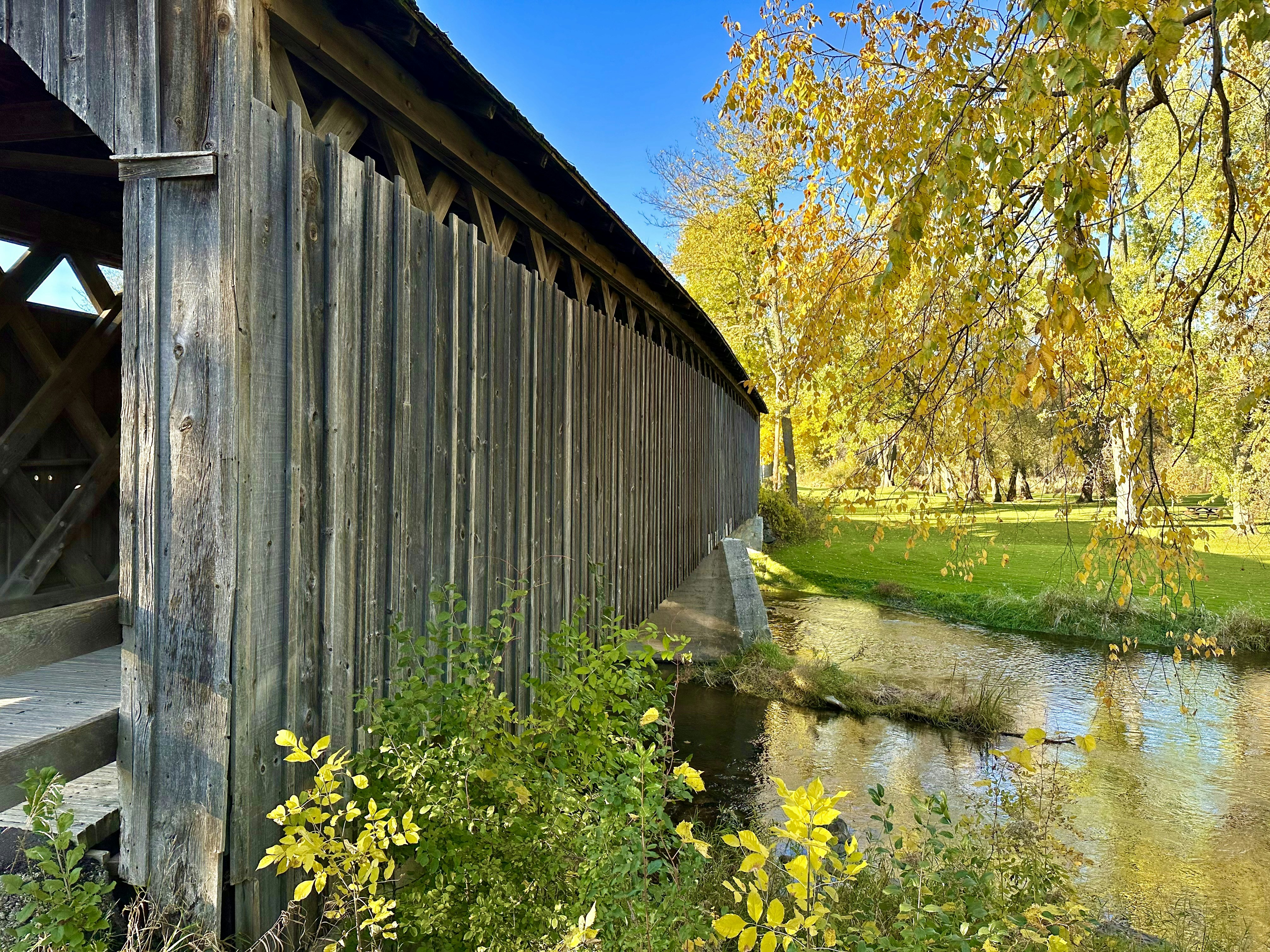 Sunlit Autumn Bridge: Weathered Wood Over a Quiet River