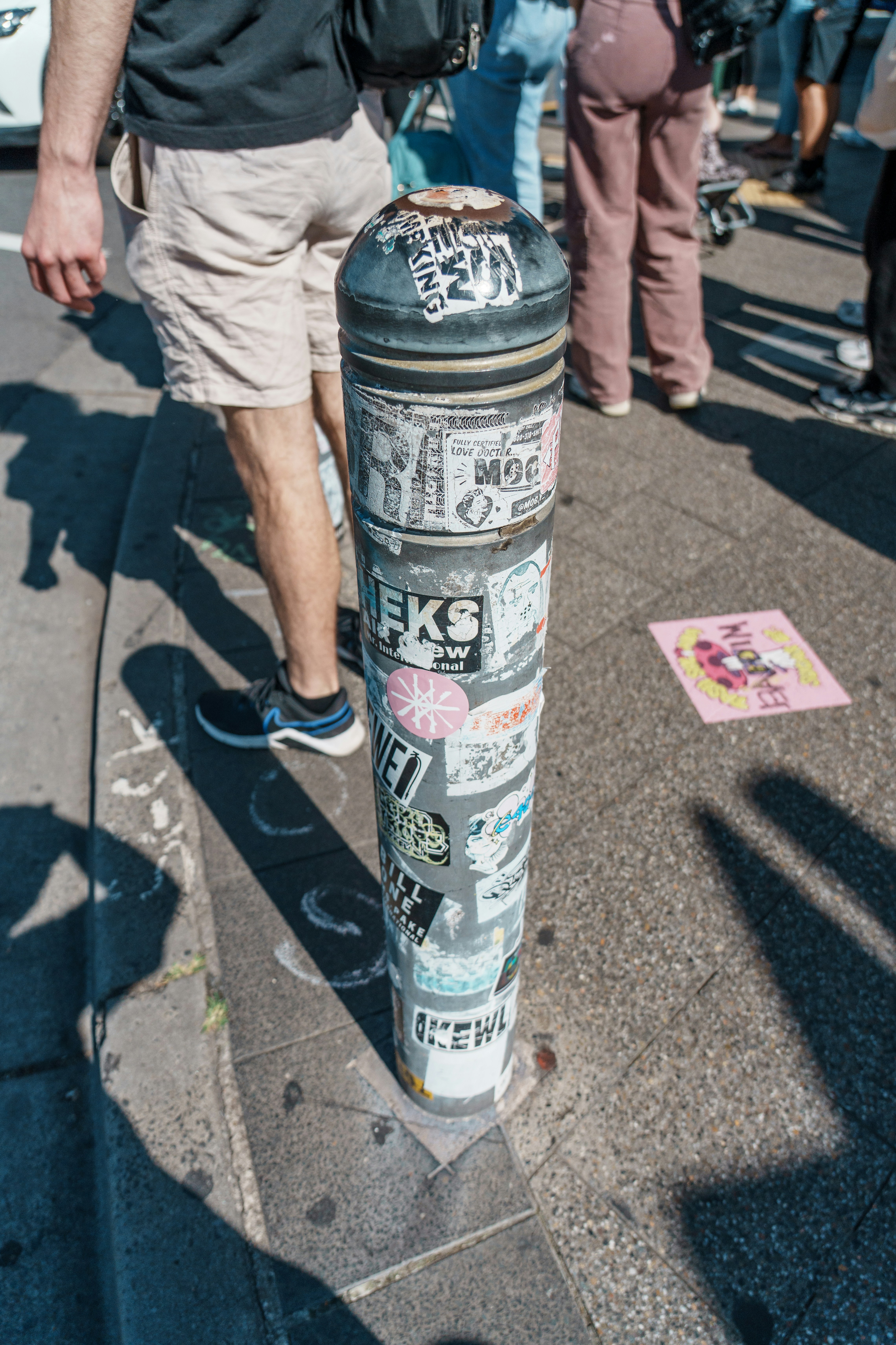 Stickered Sentinel on a Sunlit City Promenade