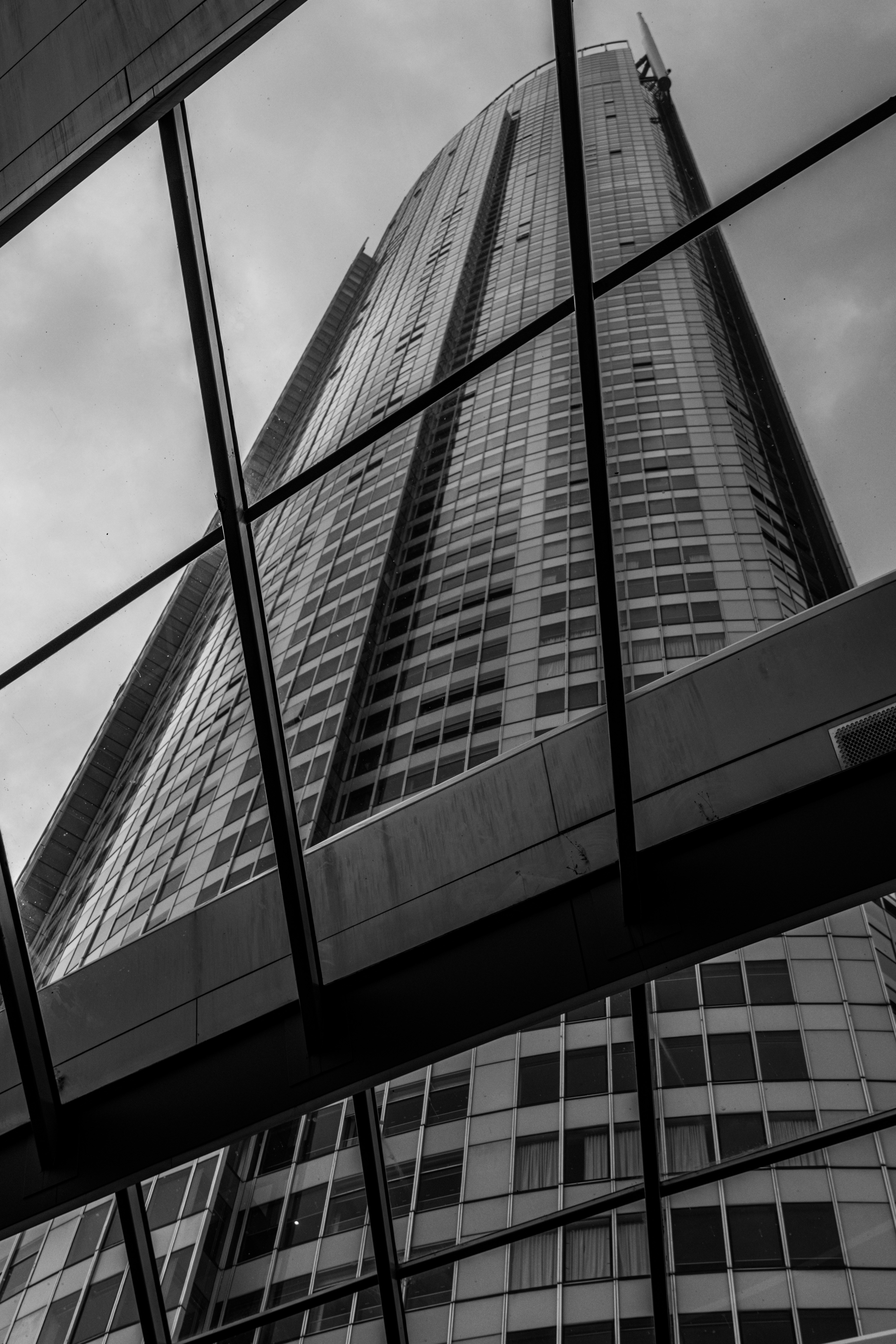 A tall building is reflected in the windows of another building photo ...