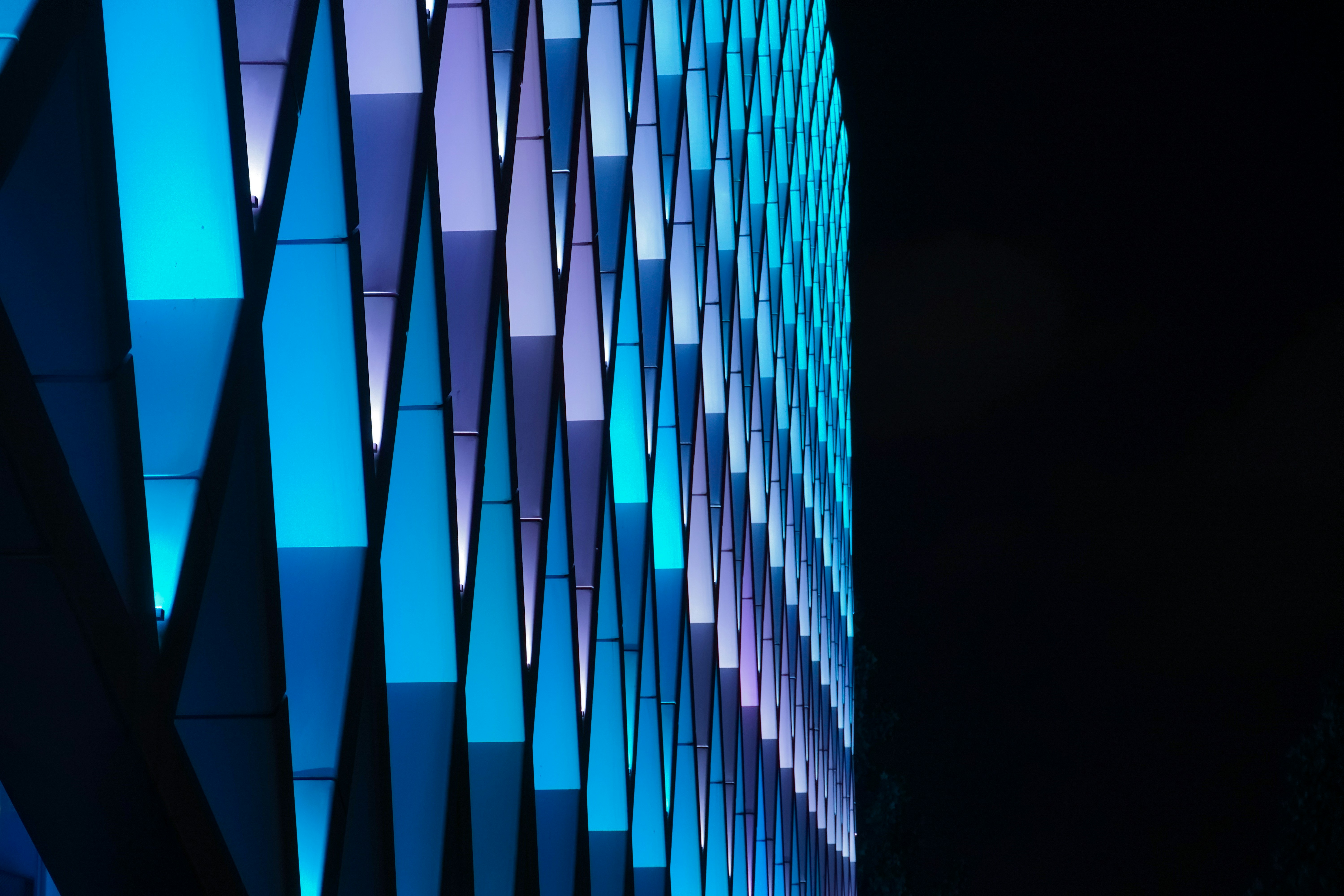A tall building lit up with blue lights photo – Free Building Image on ...