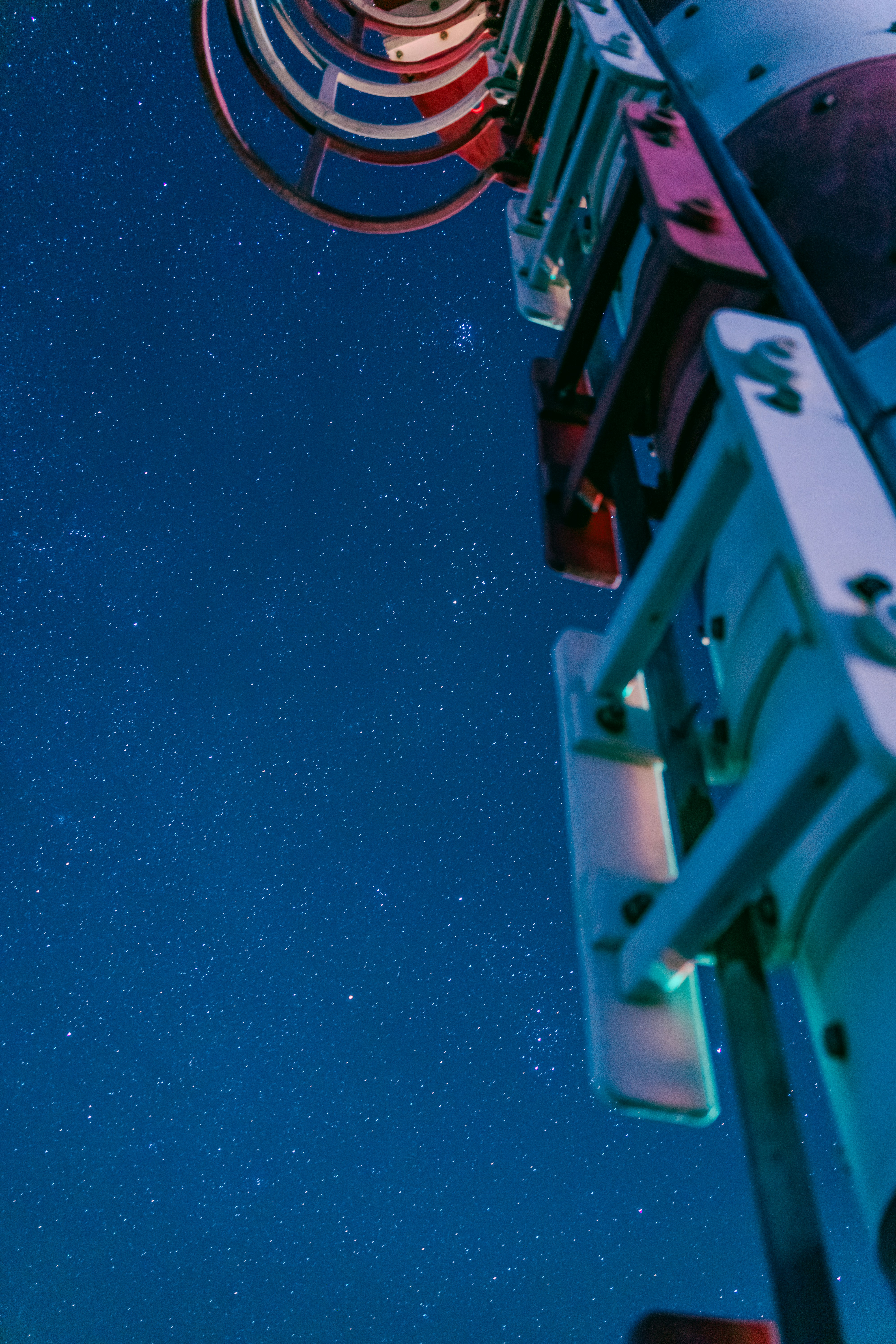 Metal tower structure illuminated under a starry night sky.