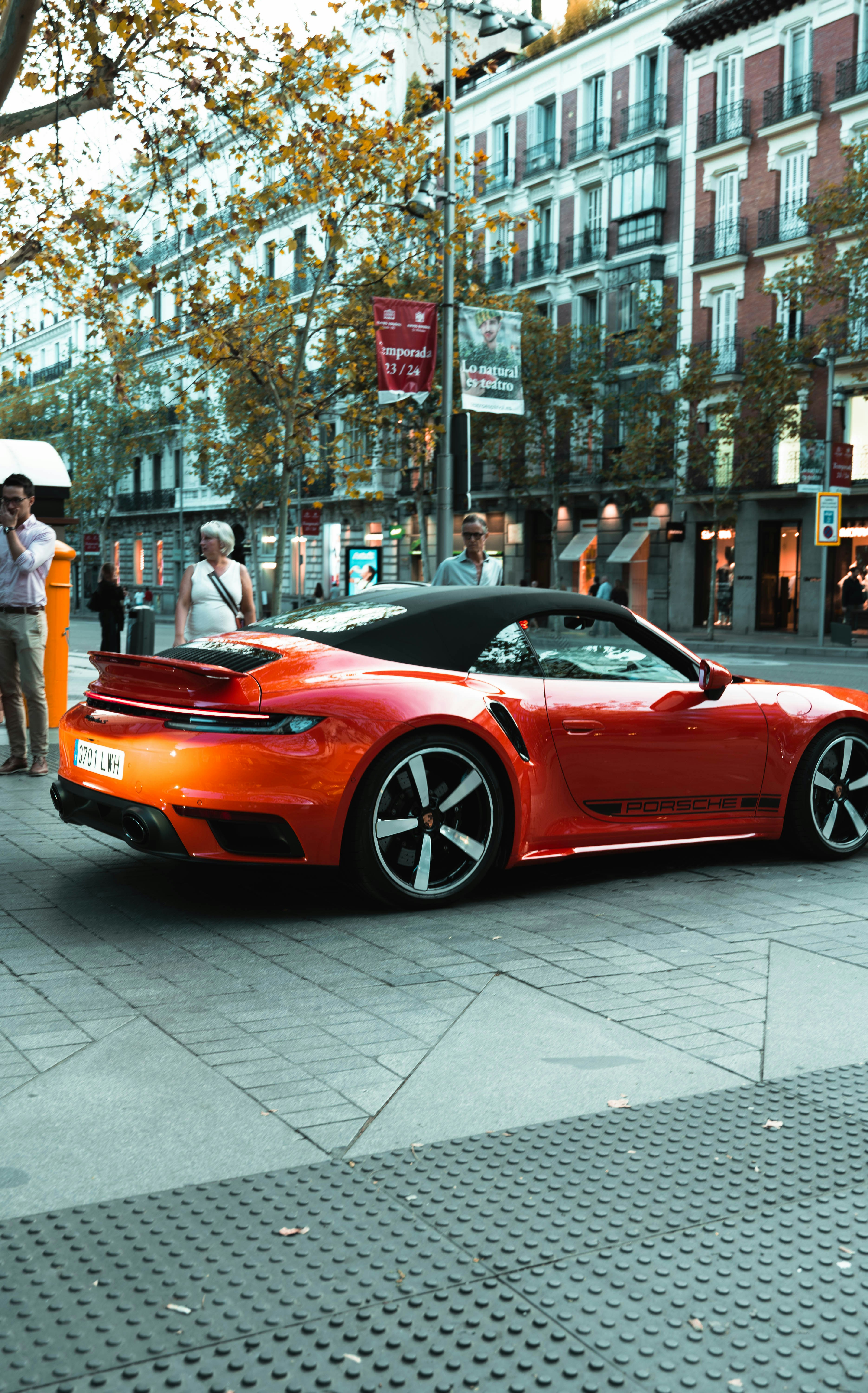 Crimson Porsche 911 Cabriolet on a Sunlit European Boulevard Amid Autumn Streets
