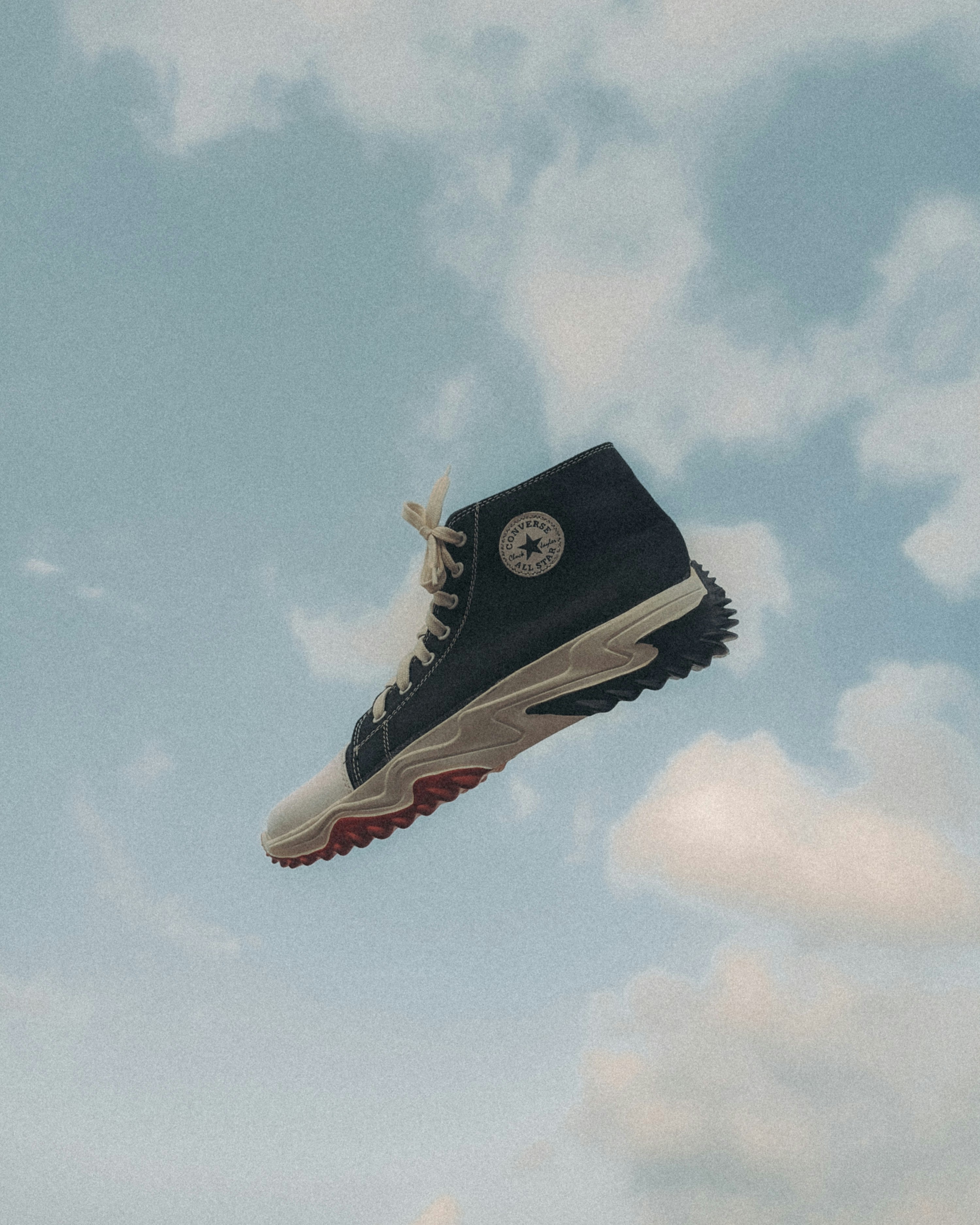 Mid-air Converse: A lone sneaker against a sunlit sky