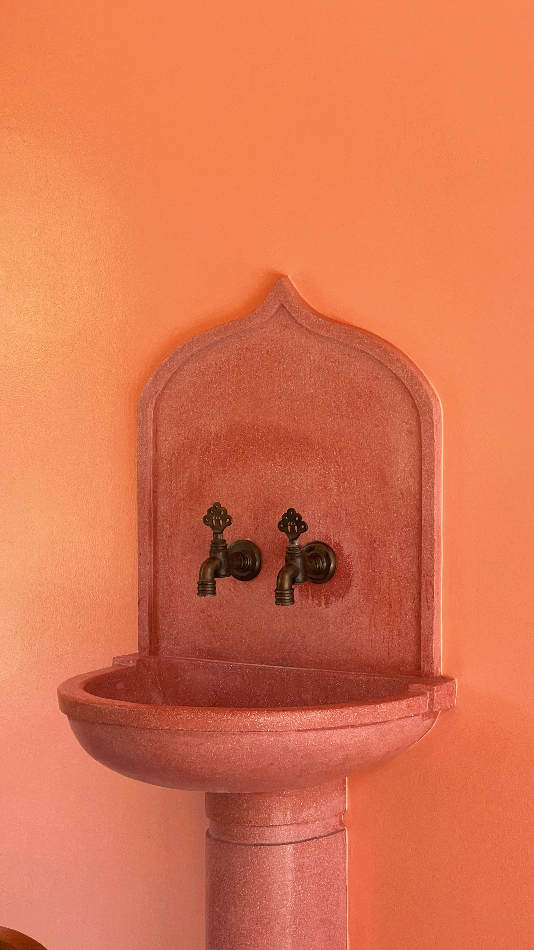 Twin Bronze Faucets on a Peach Terracotta Wall