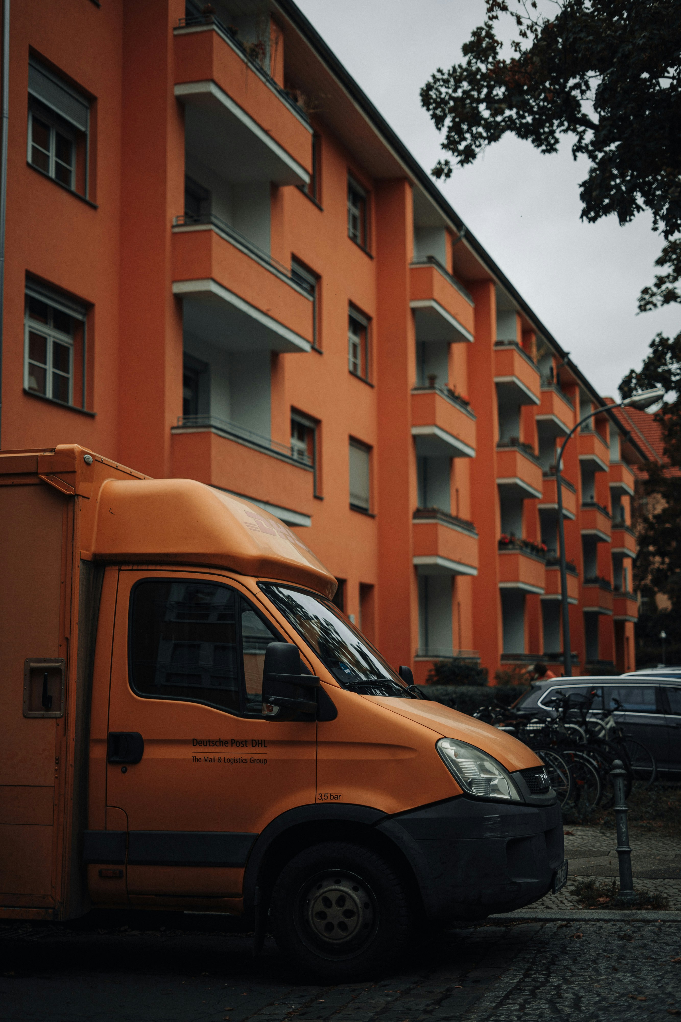 Orange Delivery Van Guards a Corridor of Balconies