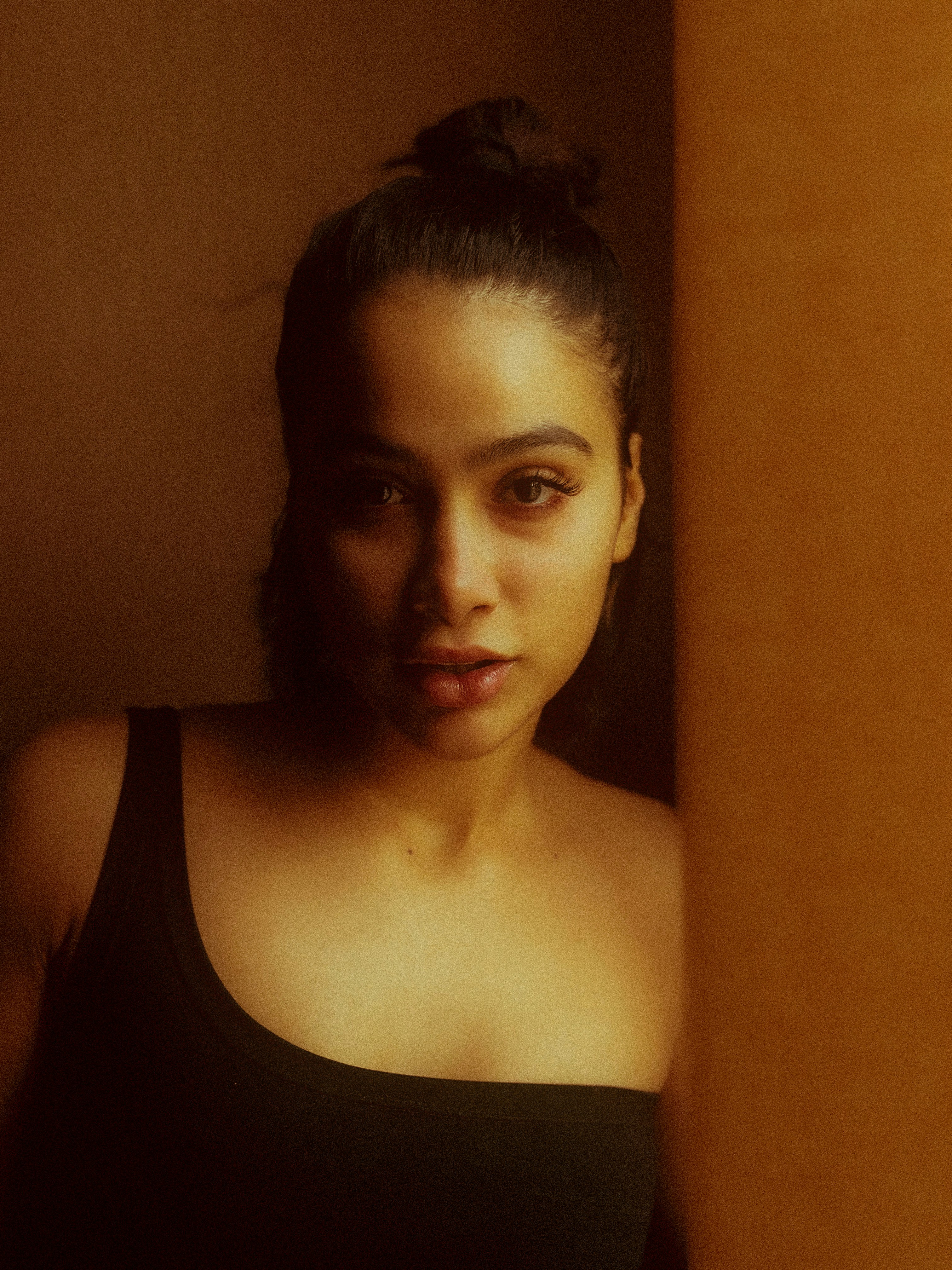 A woman in a black tank top leaning against a wall photo – Free ...