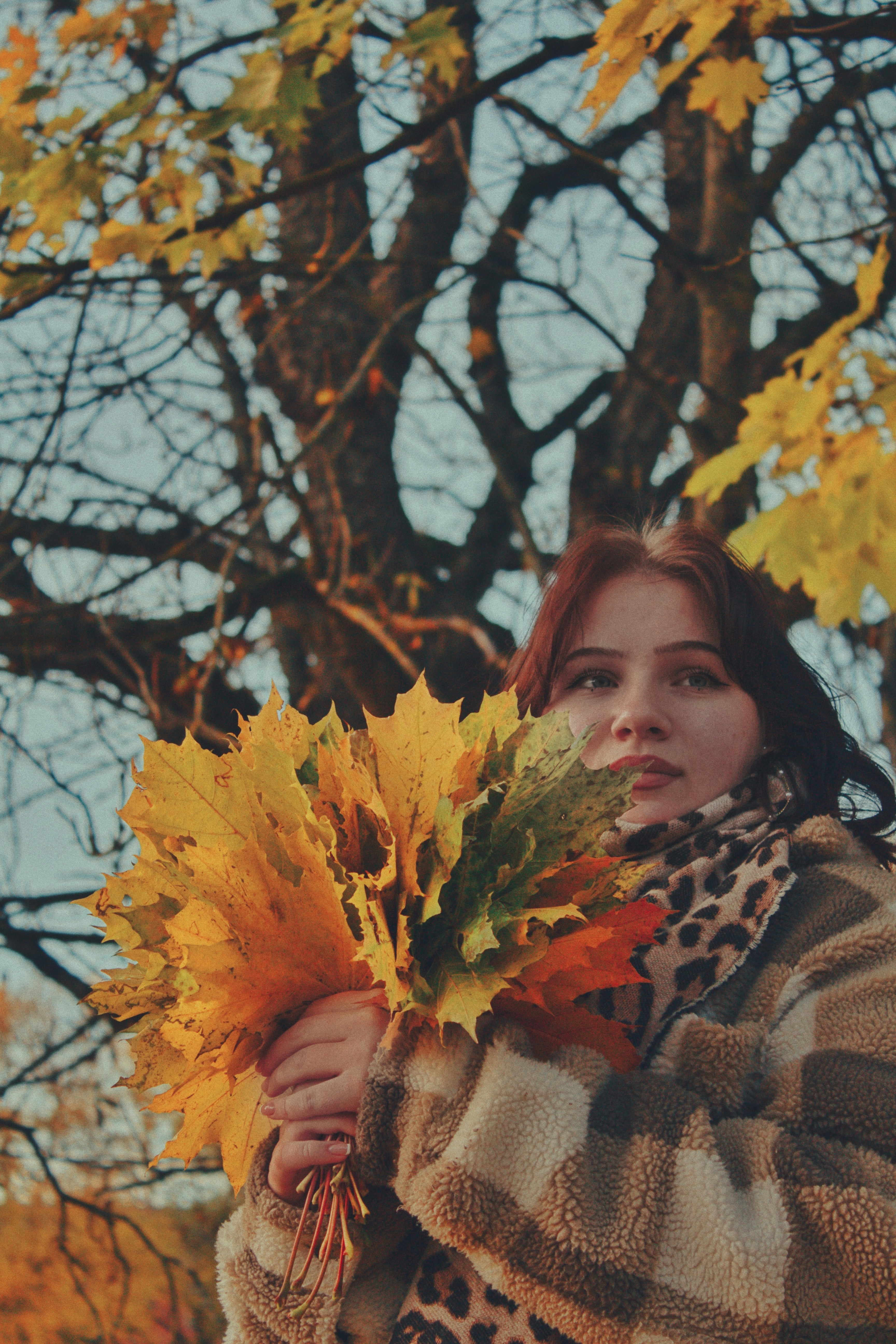 Una mujer sosteniendo un manojo de hojas frente a un árbol foto ...