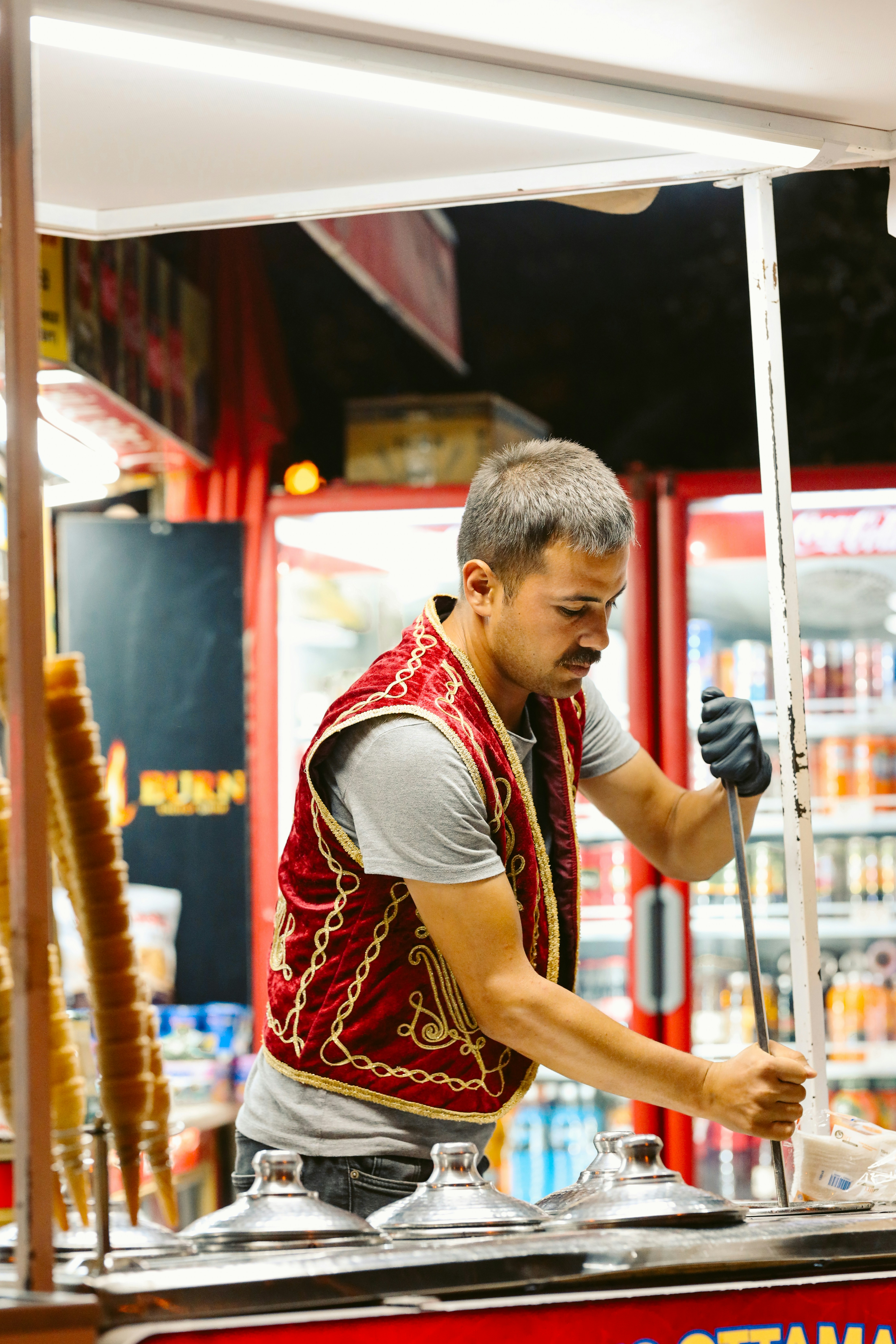 Red-Vest Vendor at a Bustling Night-Market Stall, Crafting Snacks Under Neon Light