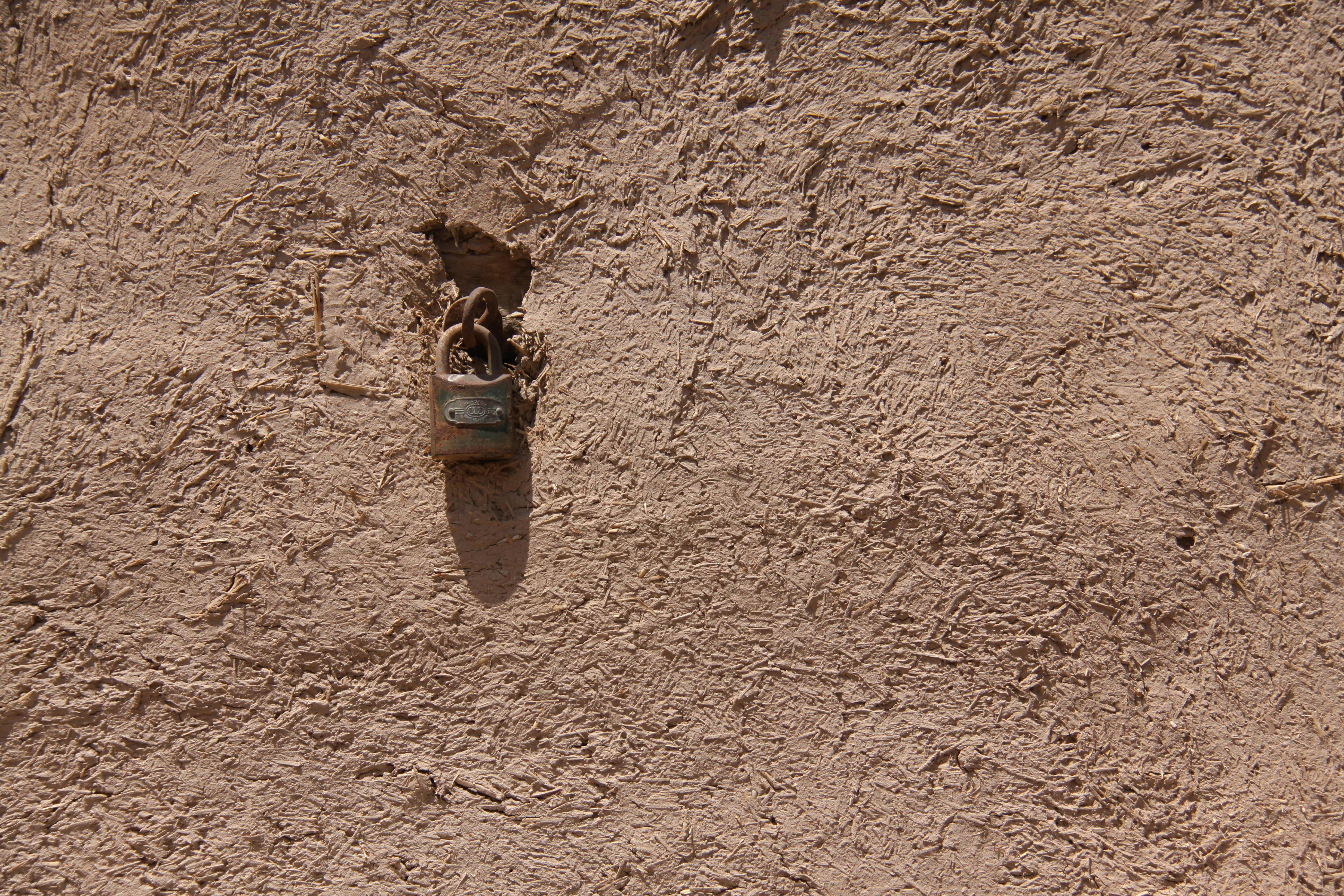 Weathered Latch on Sun-Warmed Plaster: Texture in Focus