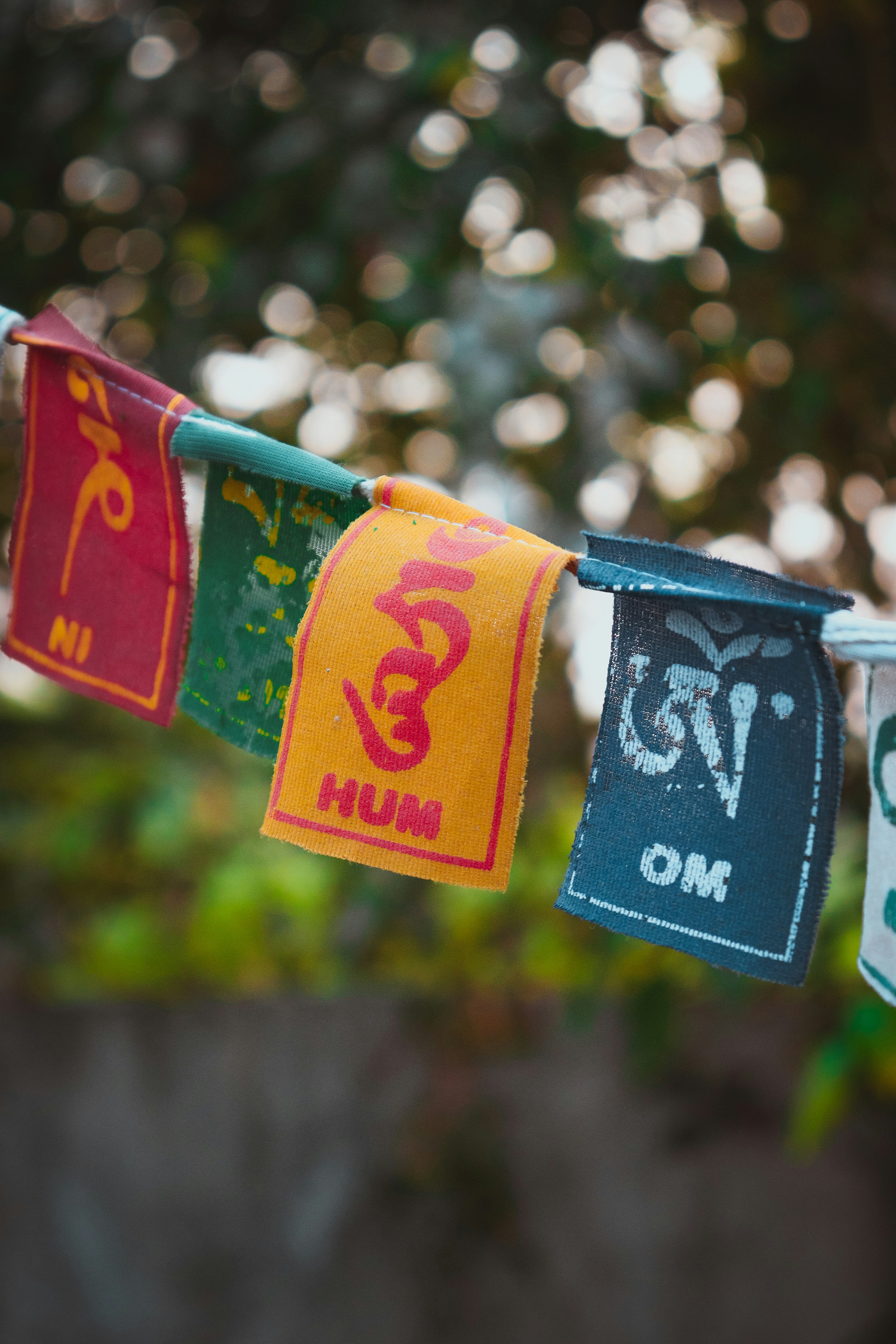 Colorful prayer flags in soft focus hues blur into a garden backdrop