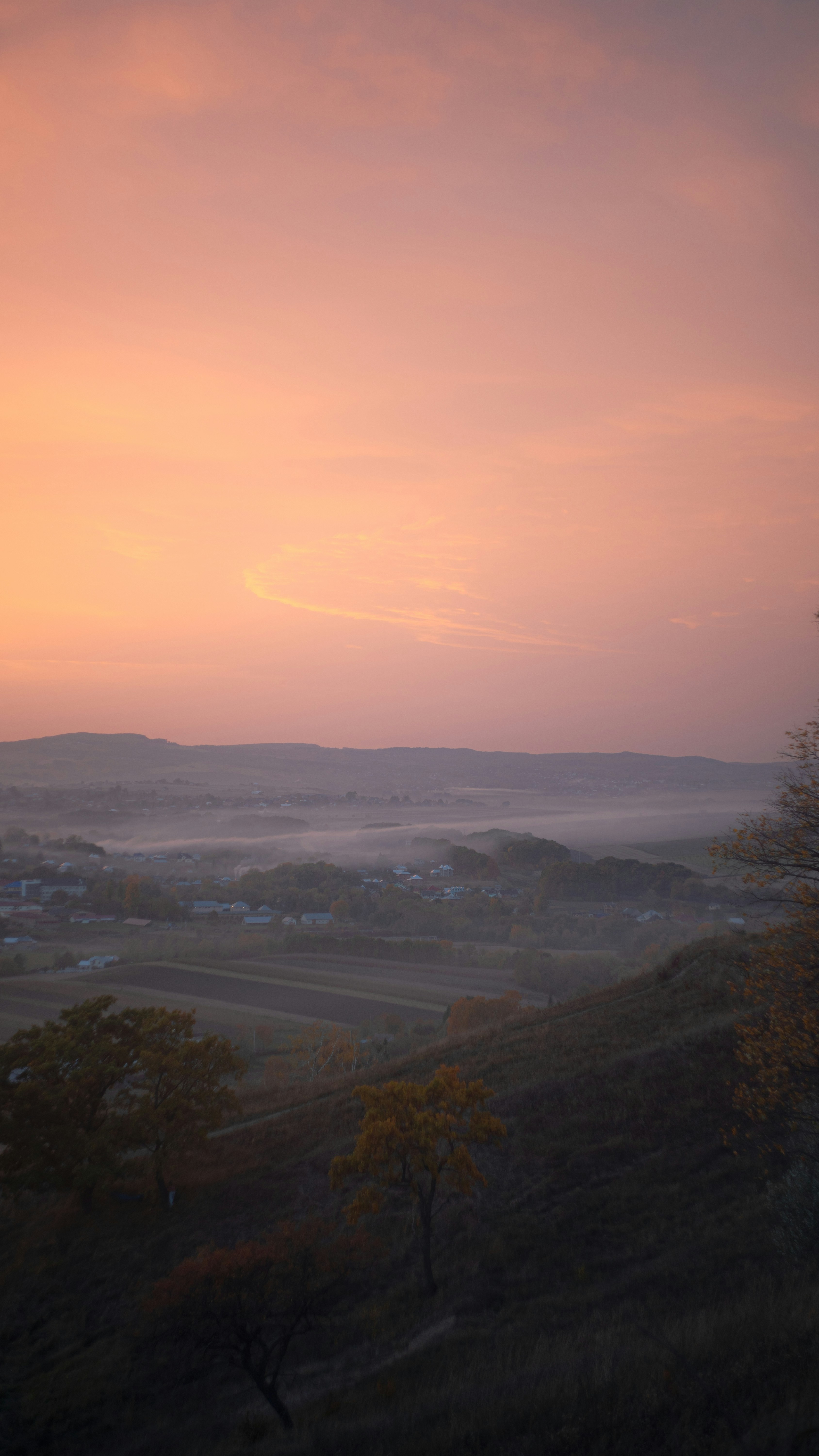 the sun is setting over a field with trees