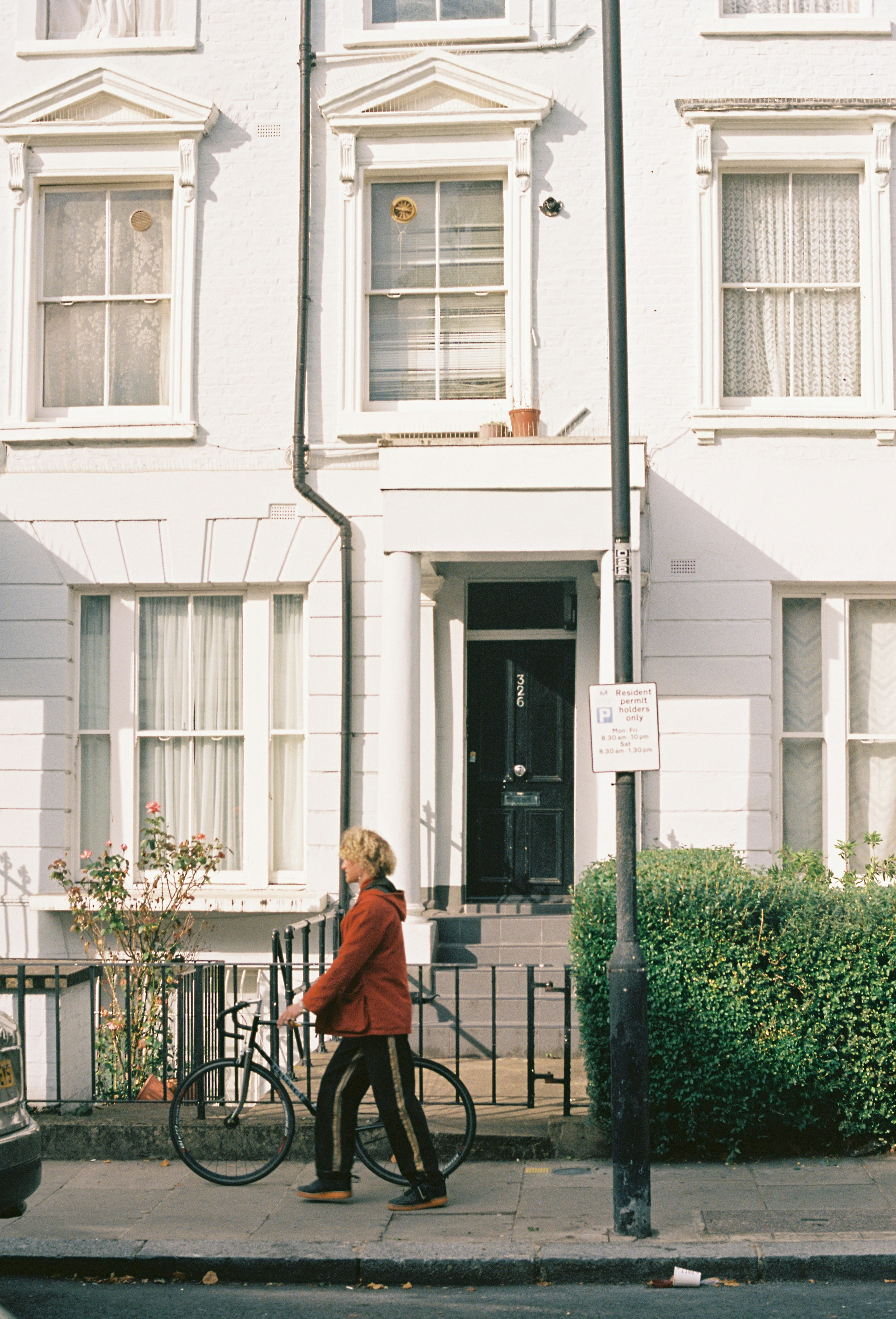 A woman walking down a street past a tall white building photo – Free ...