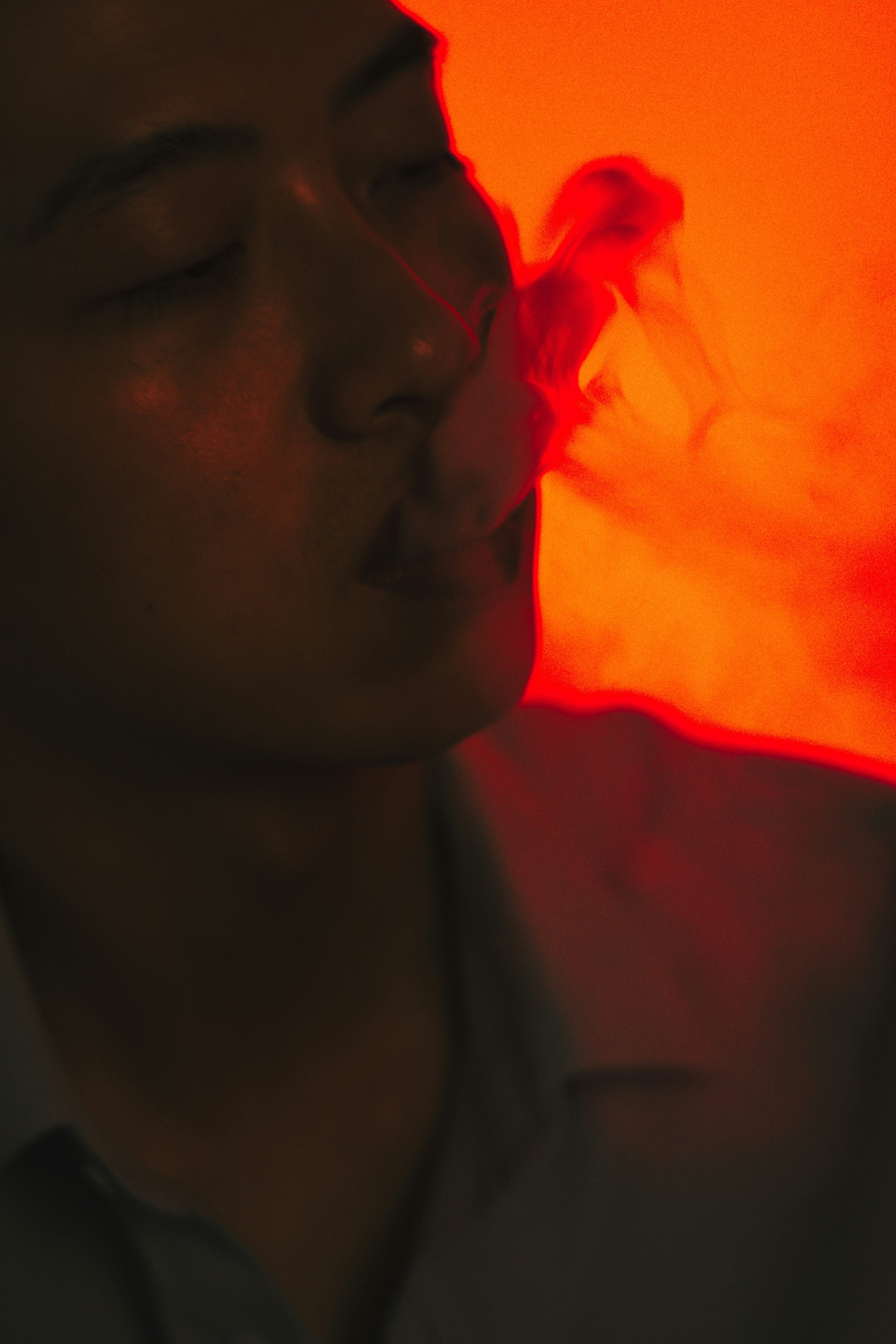 Un homme avec les yeux fermés et une lumière rouge en arrière-plan ...