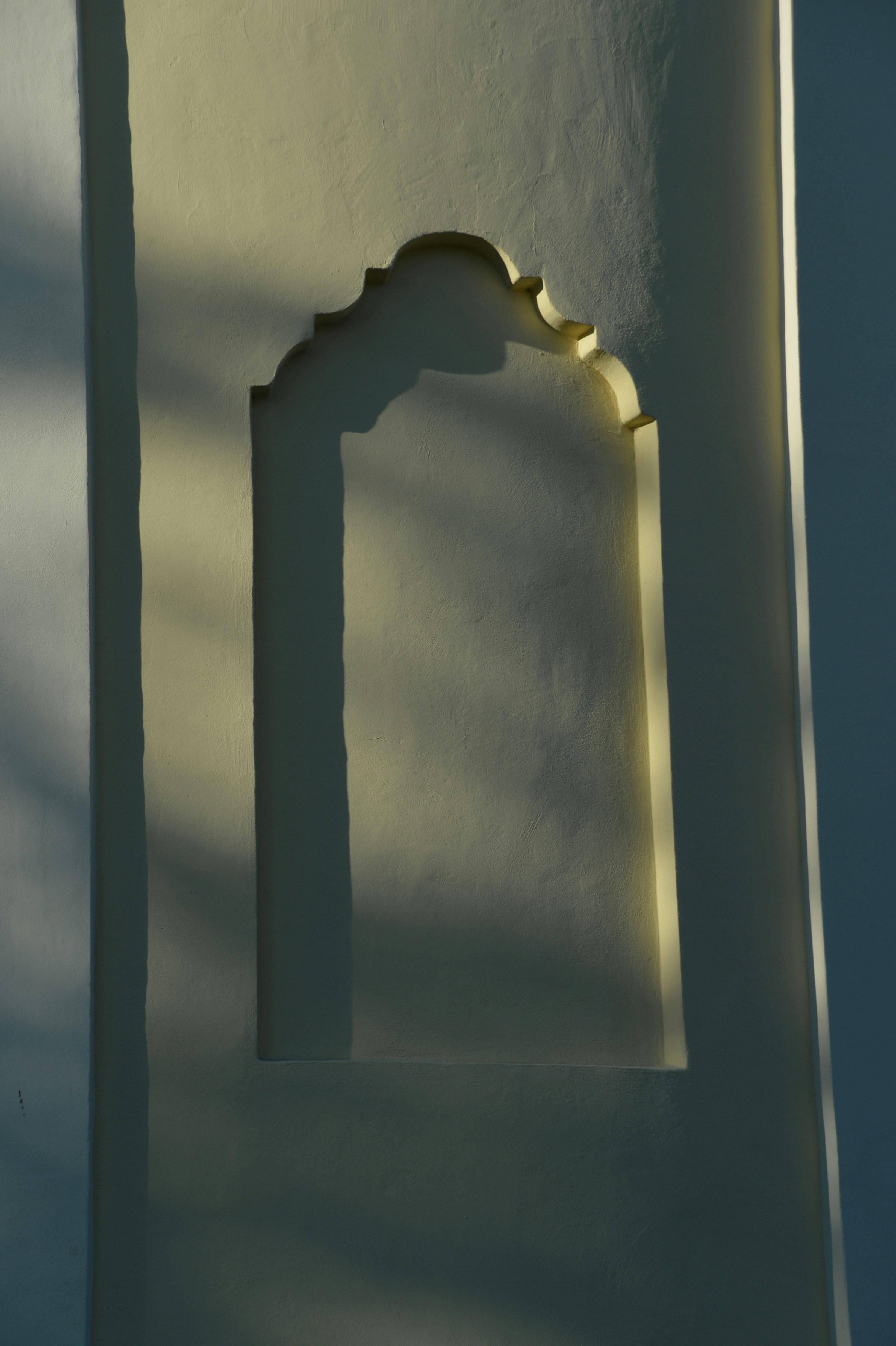 Sunlit Arch Niche: Quiet Geometry on a Pale Facade