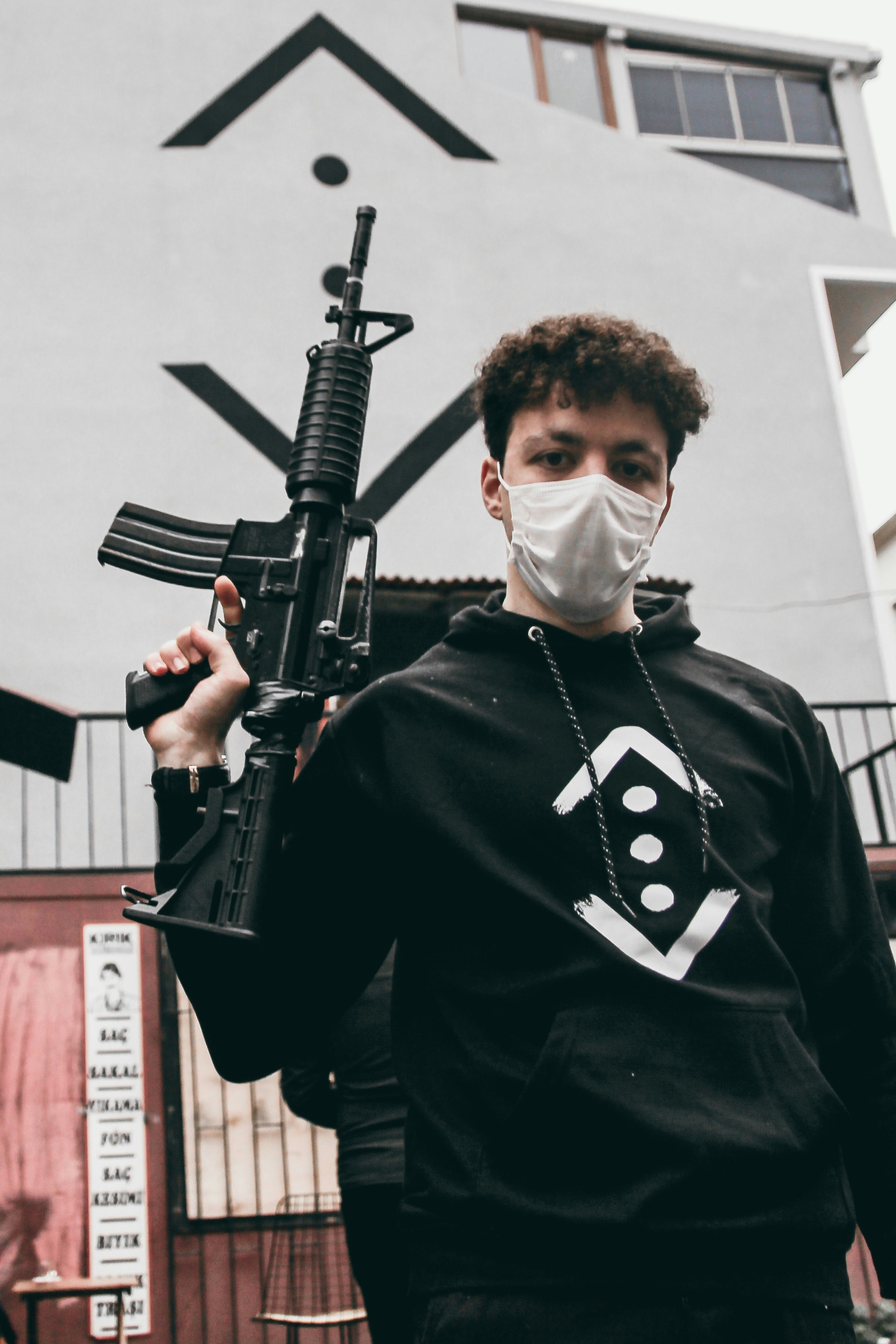 A man wearing a face mask holding a machine gun photo – Free Balat ...