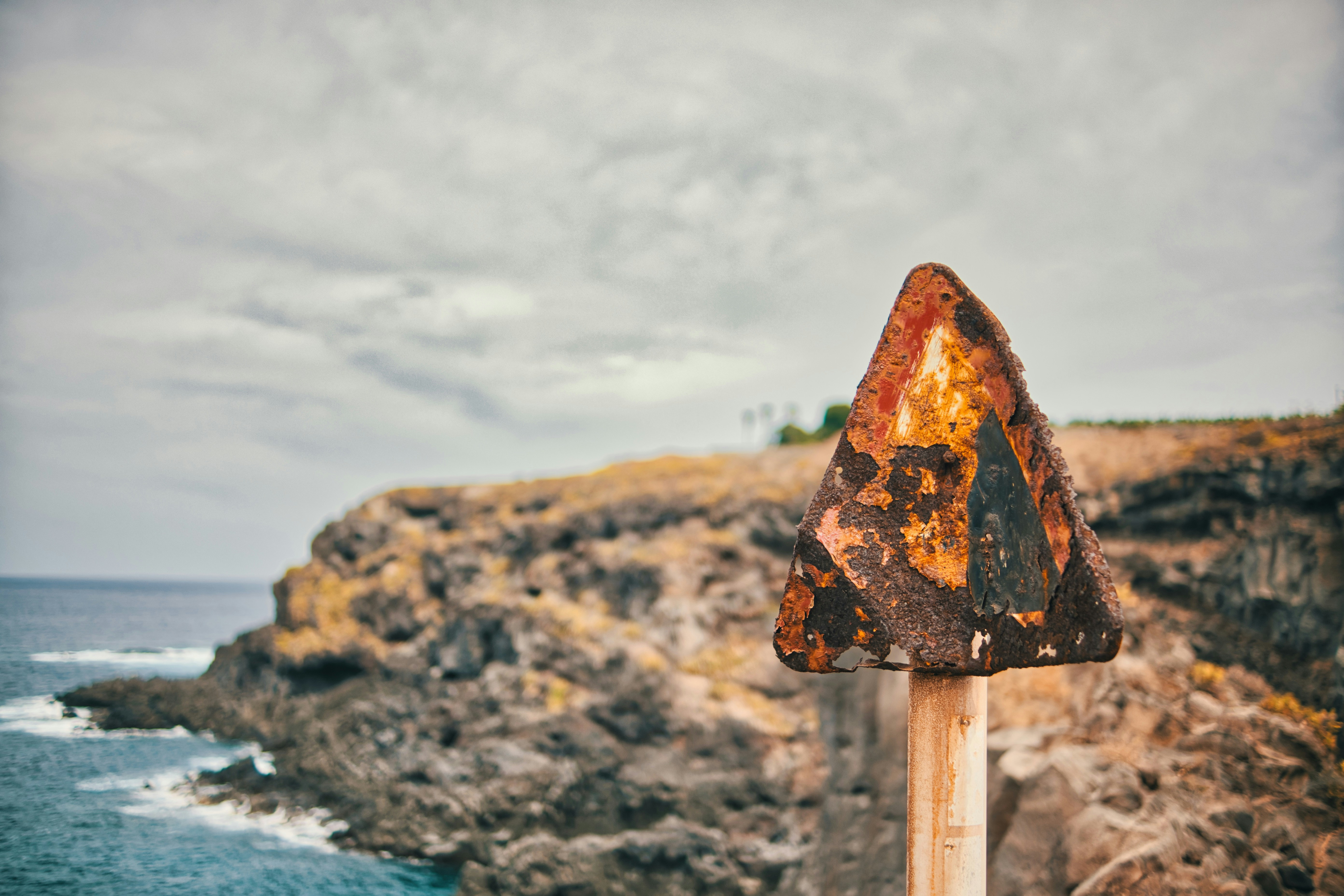 Watch out for the warning sign on the cliff, it's indicating a steep hill ahead. Take a moment to appreciate the stunning sky, water, and rock formations while staying cautious. #beach #ocean #sky #water #rock #landscape #nature #coast #safety